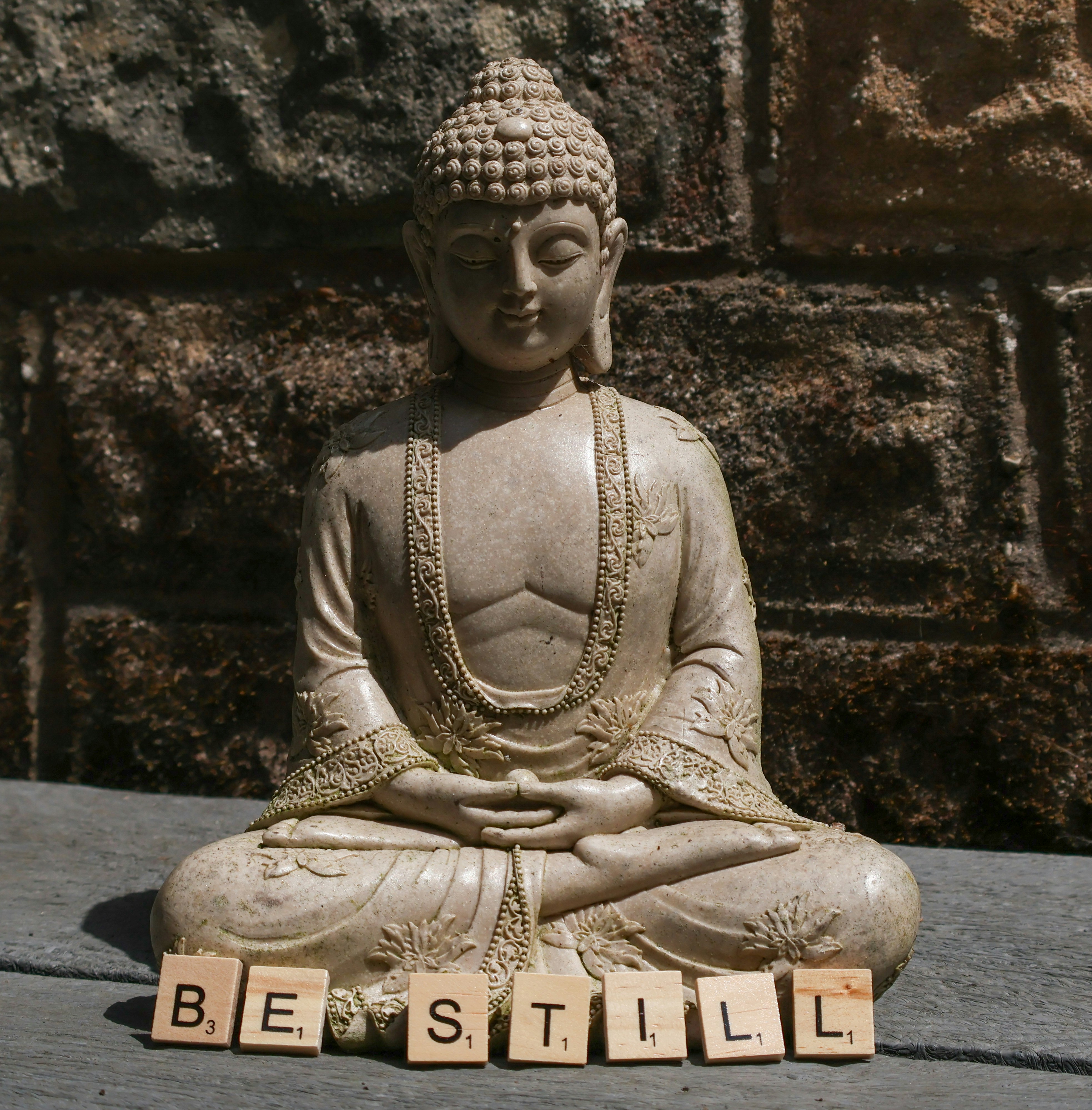 Stillness in Stone: A Meditating Buddha Amid Brick Backdrop