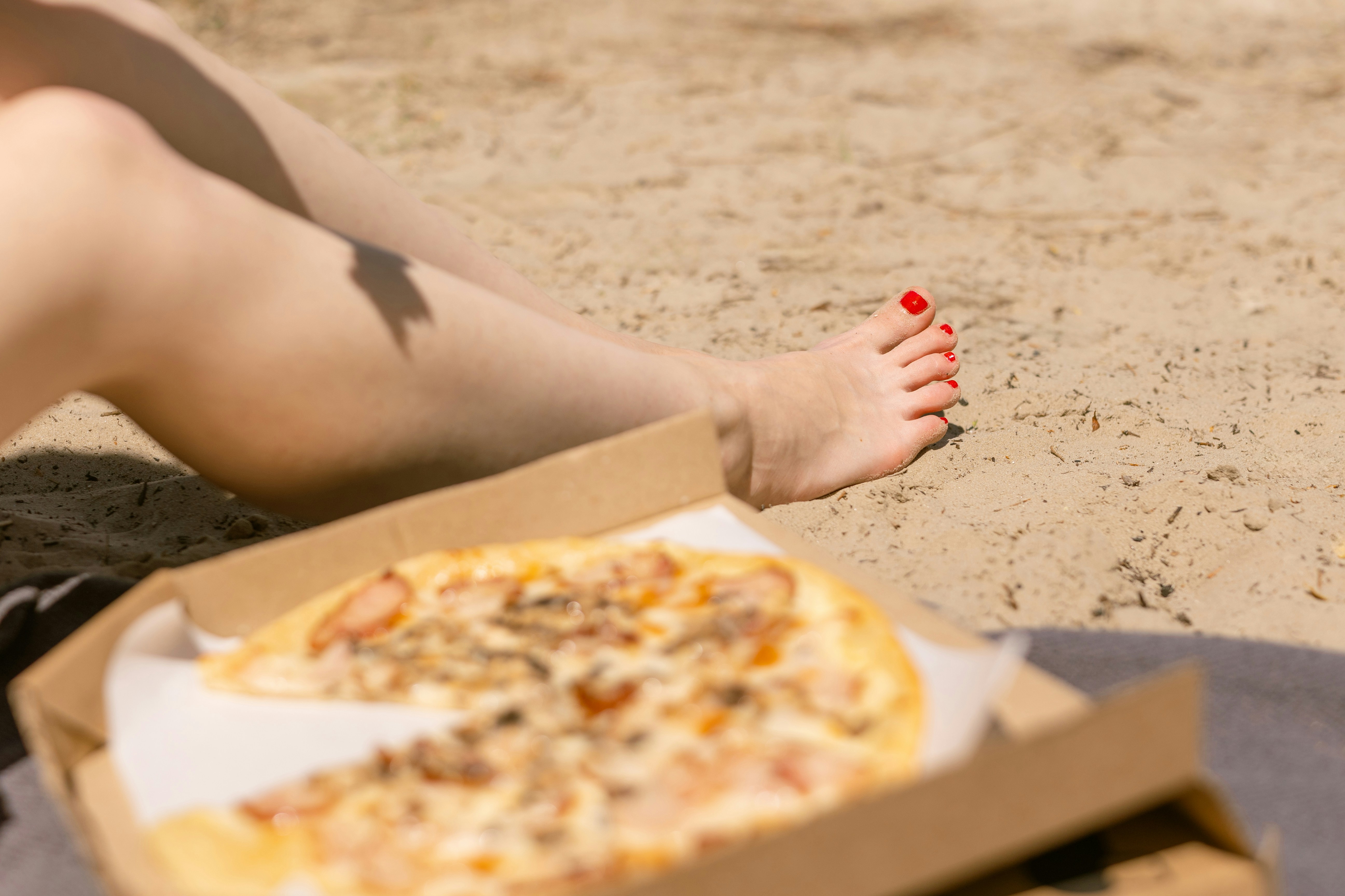 Sunlit Beach Paused: A Plate of Pizza and a Painted Toe