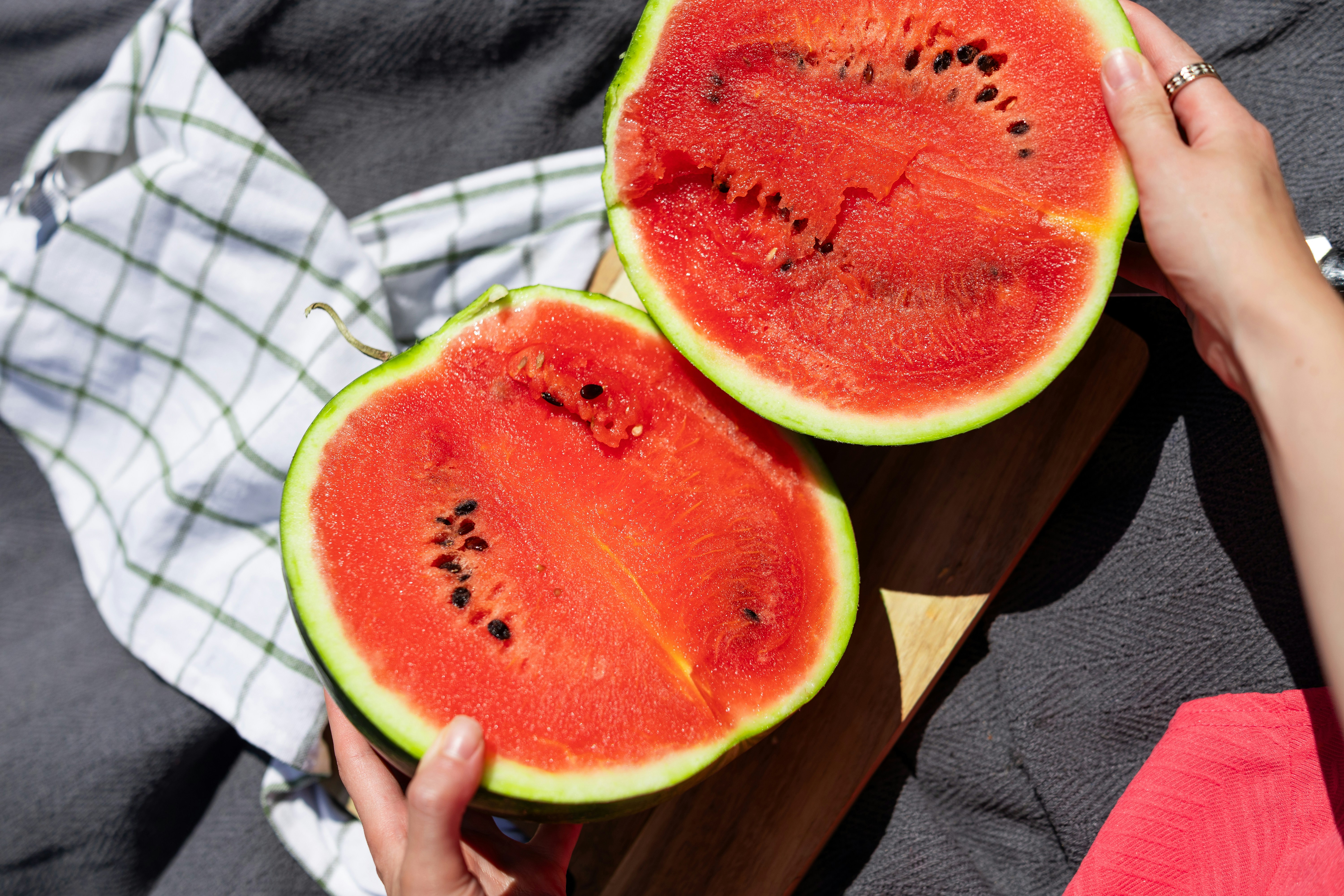 Juicy halves of watermelon anchored by a sunlit hand
