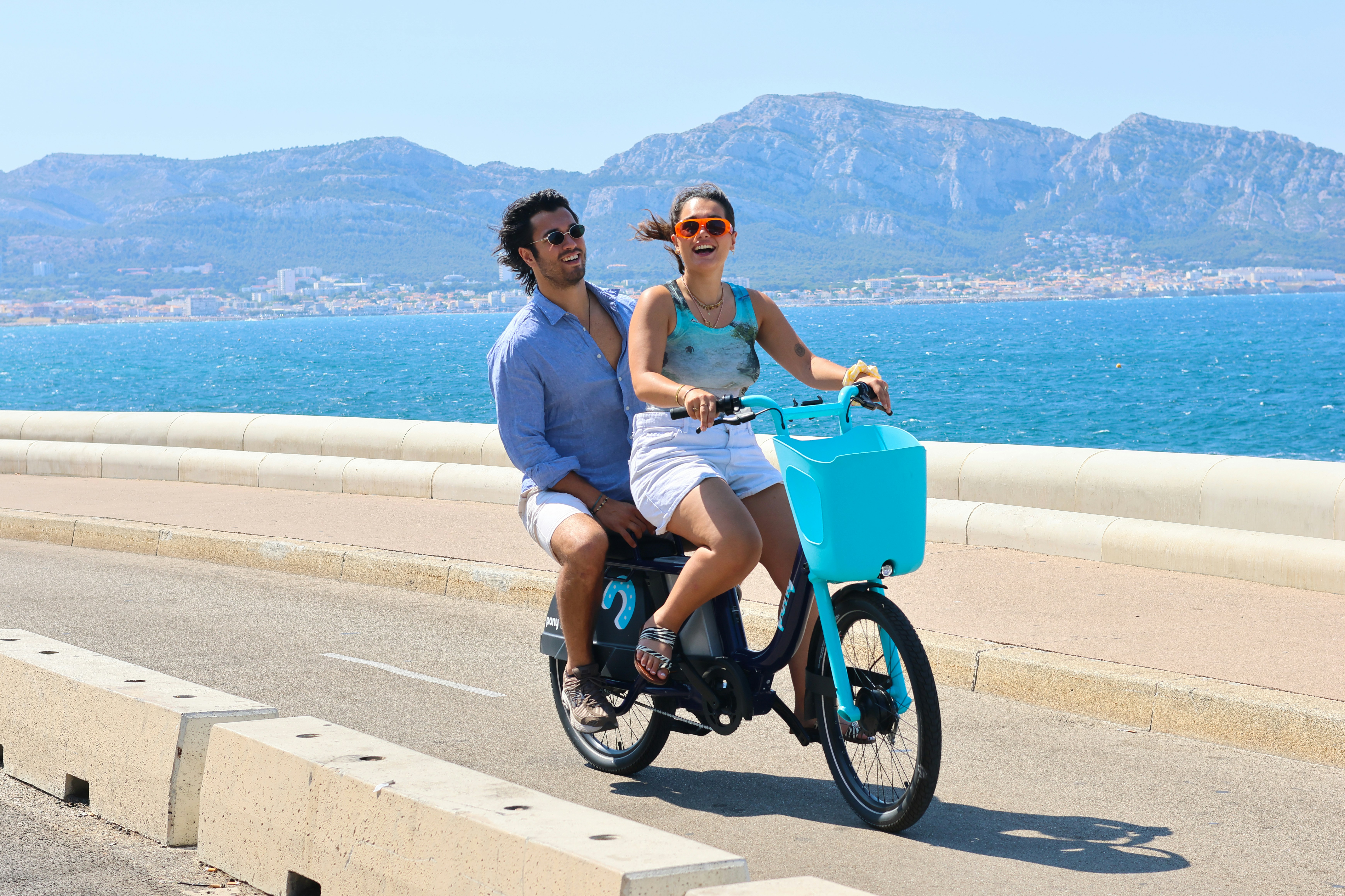 Sunlit Ride by the Sea: A Couple on a Bright Coastal Bicycle