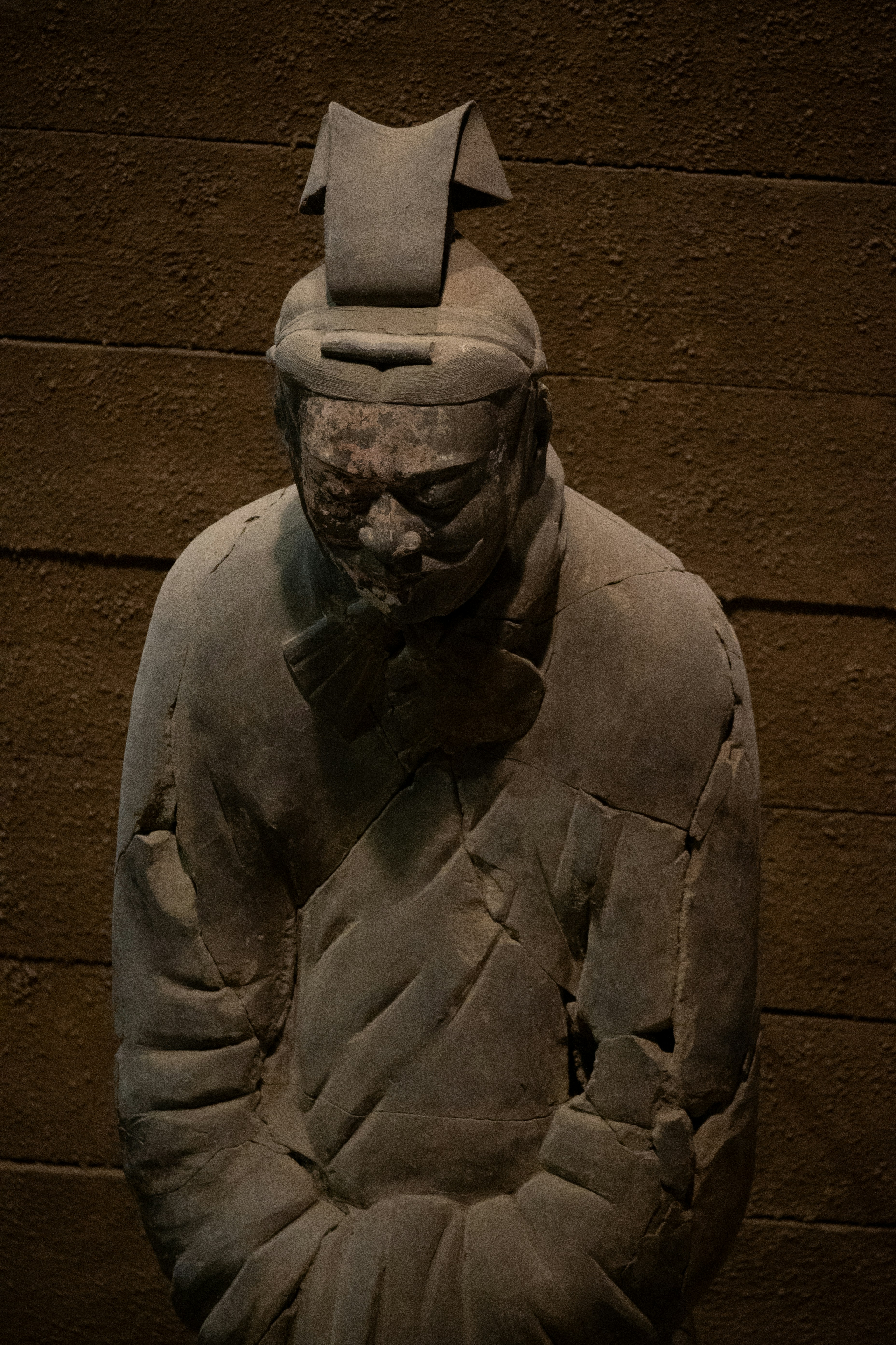 Fragmented Warrior: A Moss-Covered Terracotta Figure in Dim Light