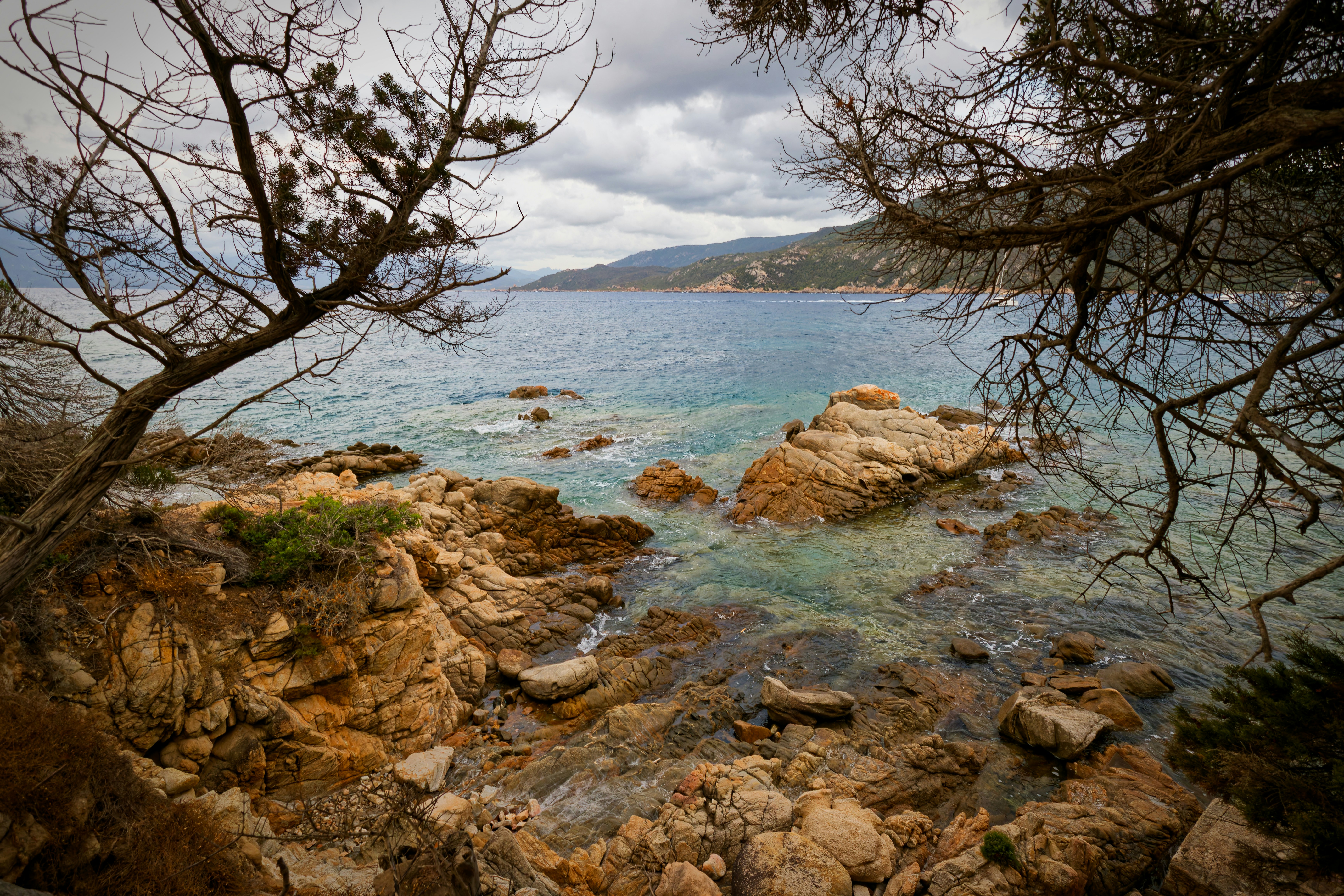 Rugged shoreline opens to turquoise depths under stormy skies