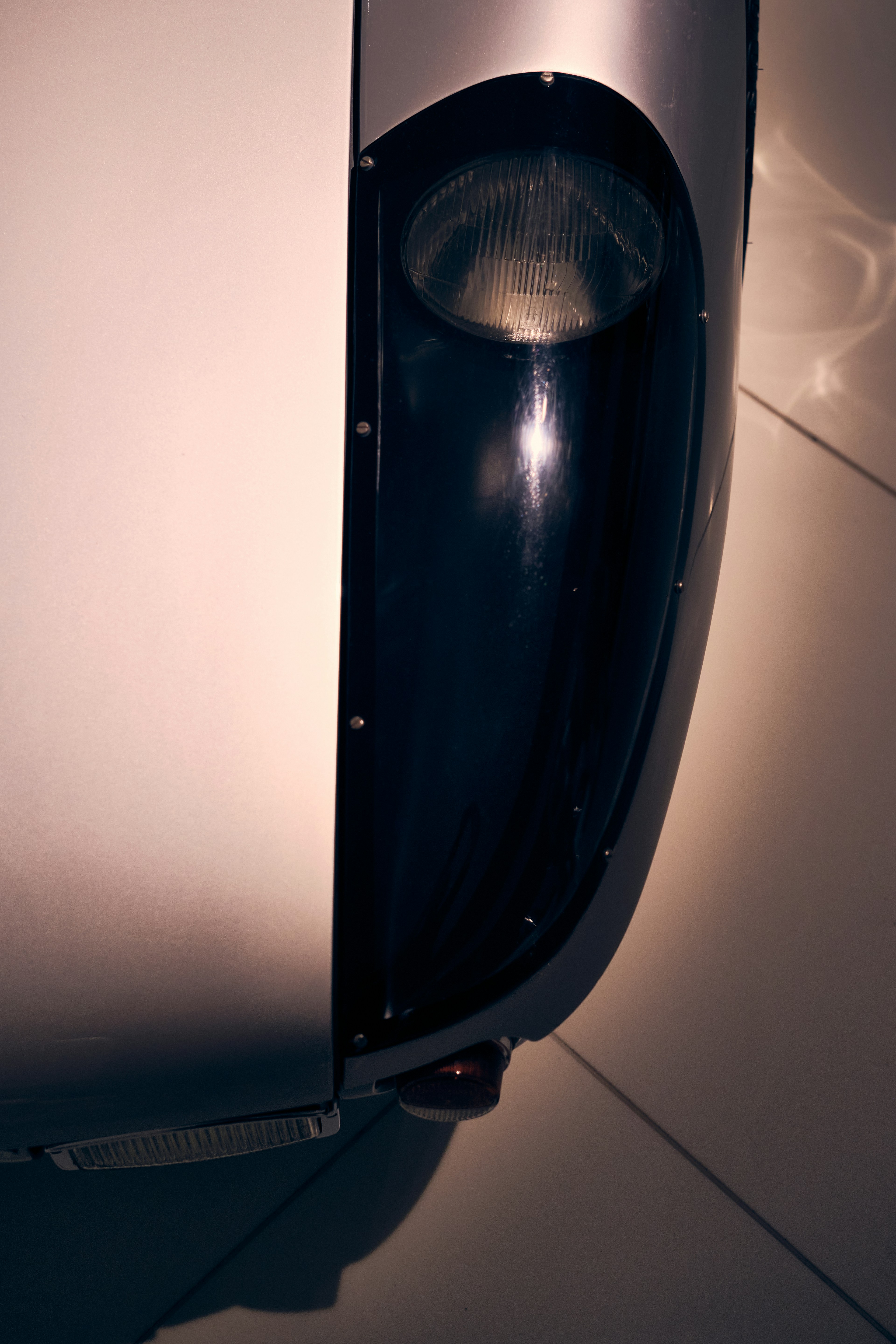 Curved chrome and shadow: a vintage car’s front edge in muted light