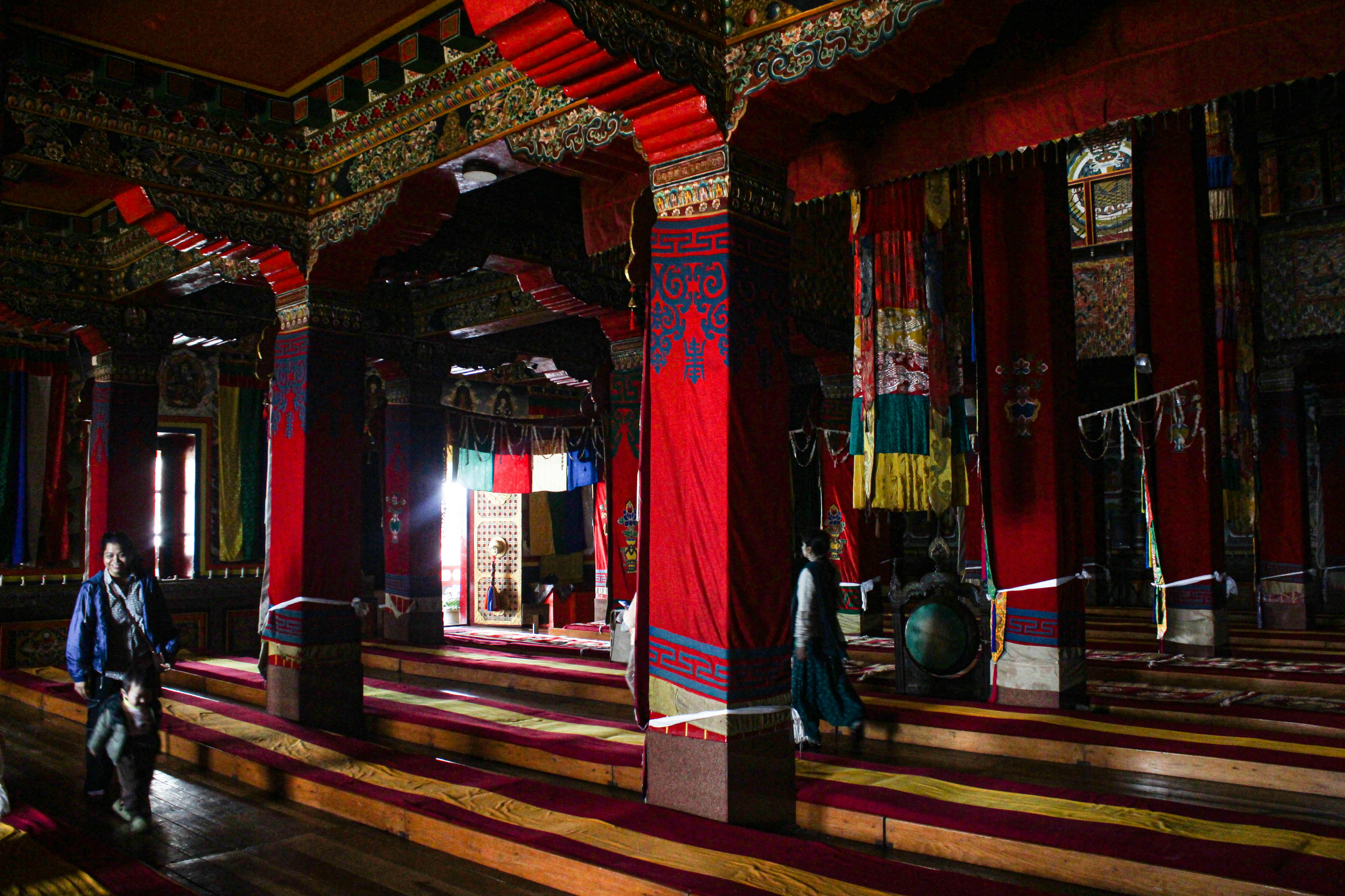 The interior of the Tawang Monastery in Arunachal Pradesh, India. It is known as the largest monastery in India and the second largest in the world. The interior features rows of prayer cushions, intricate paintings of deities on the walls, and a large assembly hall. Founded in the 17th century, the monastery holds centuries of ancient scriptures and is a significant cultural center.