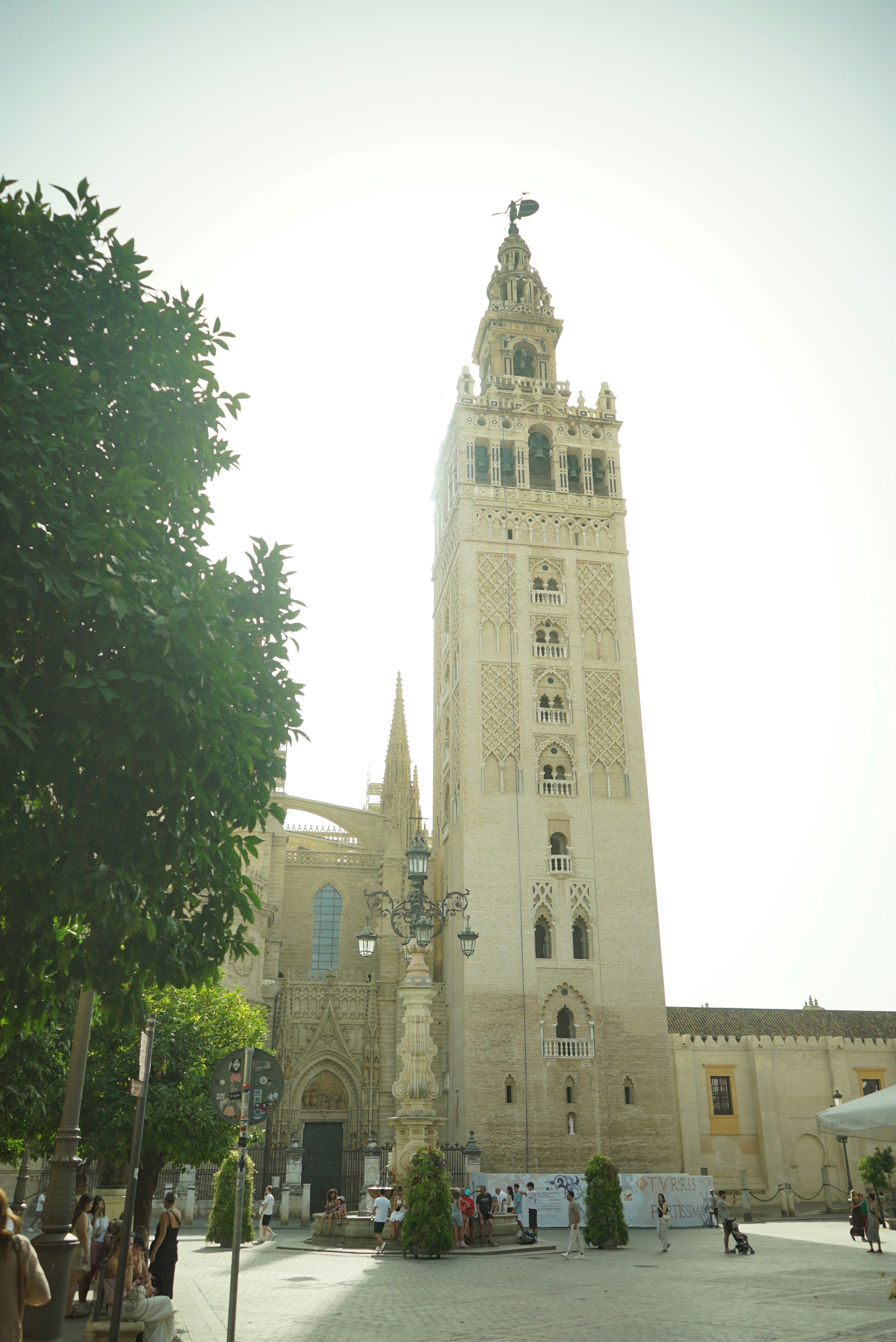 La Giralda dominates the skyline of Seville beside the cathedral, illuminated by soft morning light against a bright summer sky. Descripción en español: La Giralda domina el perfil urbano de Sevilla junto a la catedral, iluminada por la suave luz matinal bajo un brillante cielo de verano.