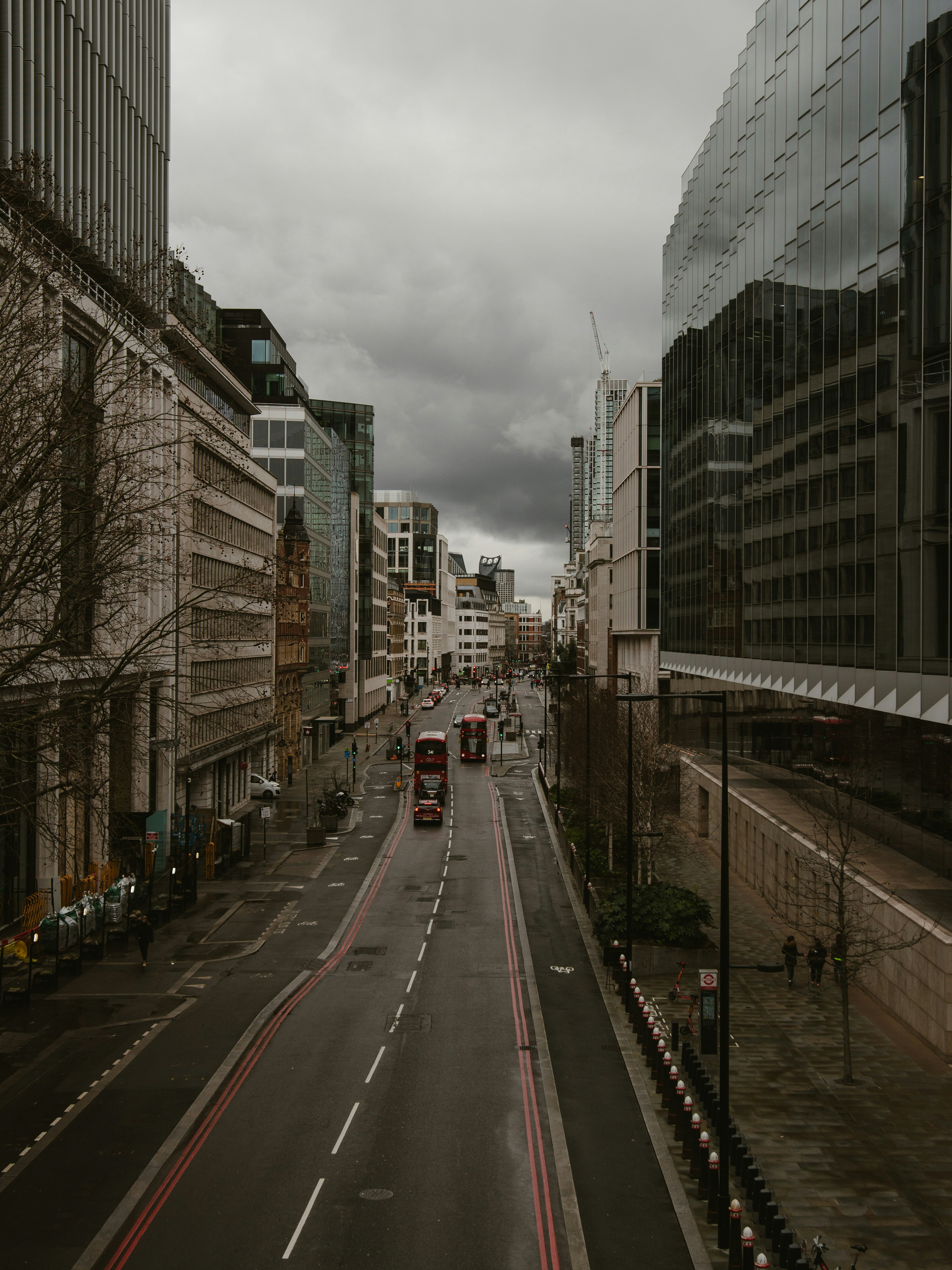 Urban street valley framed by glass-fronted towers with a central roadway and distant cityscape, captured from a high vantage point.