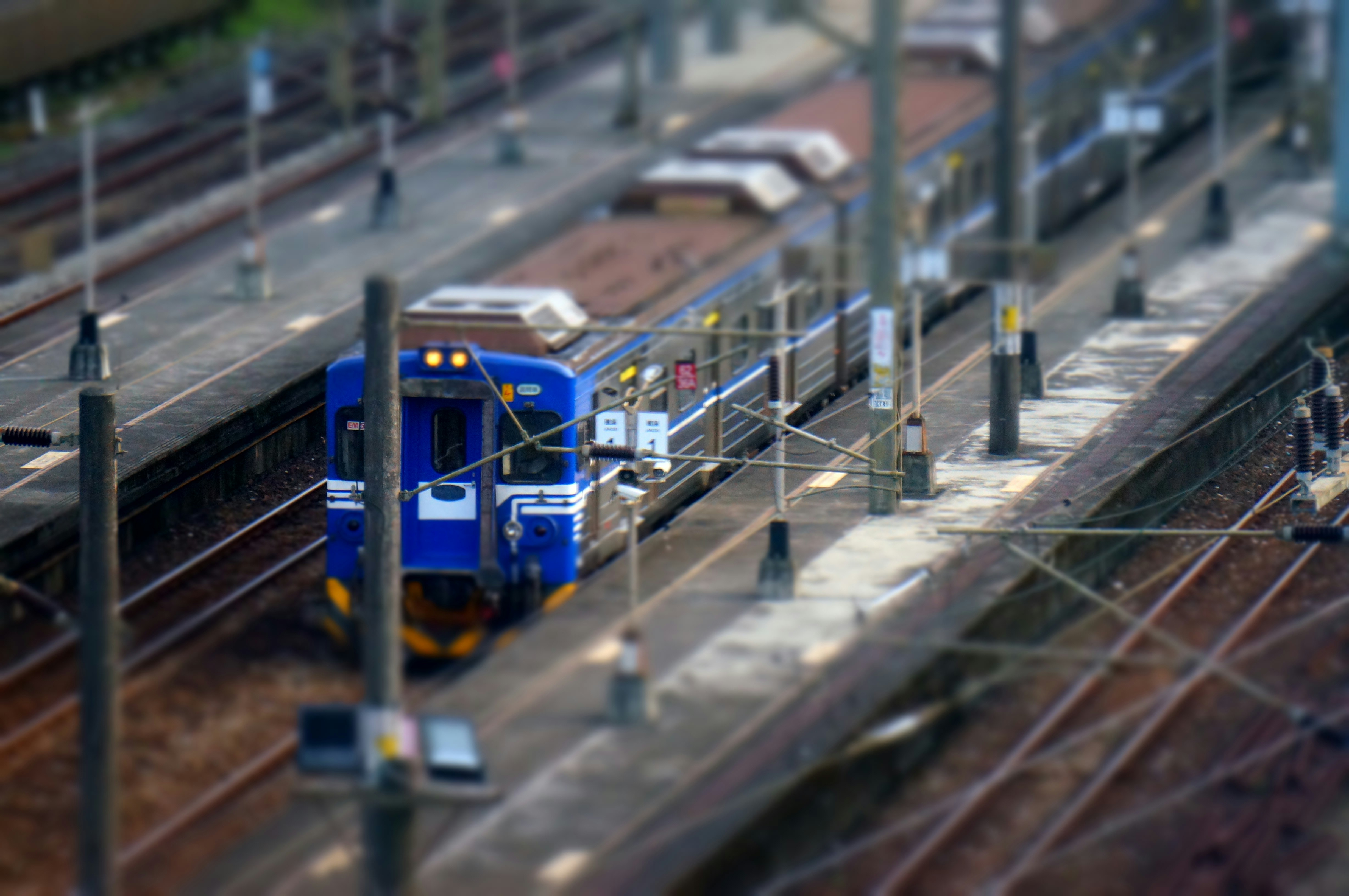Blue commuter at a tilted station: a miniature-like city railcar in focus