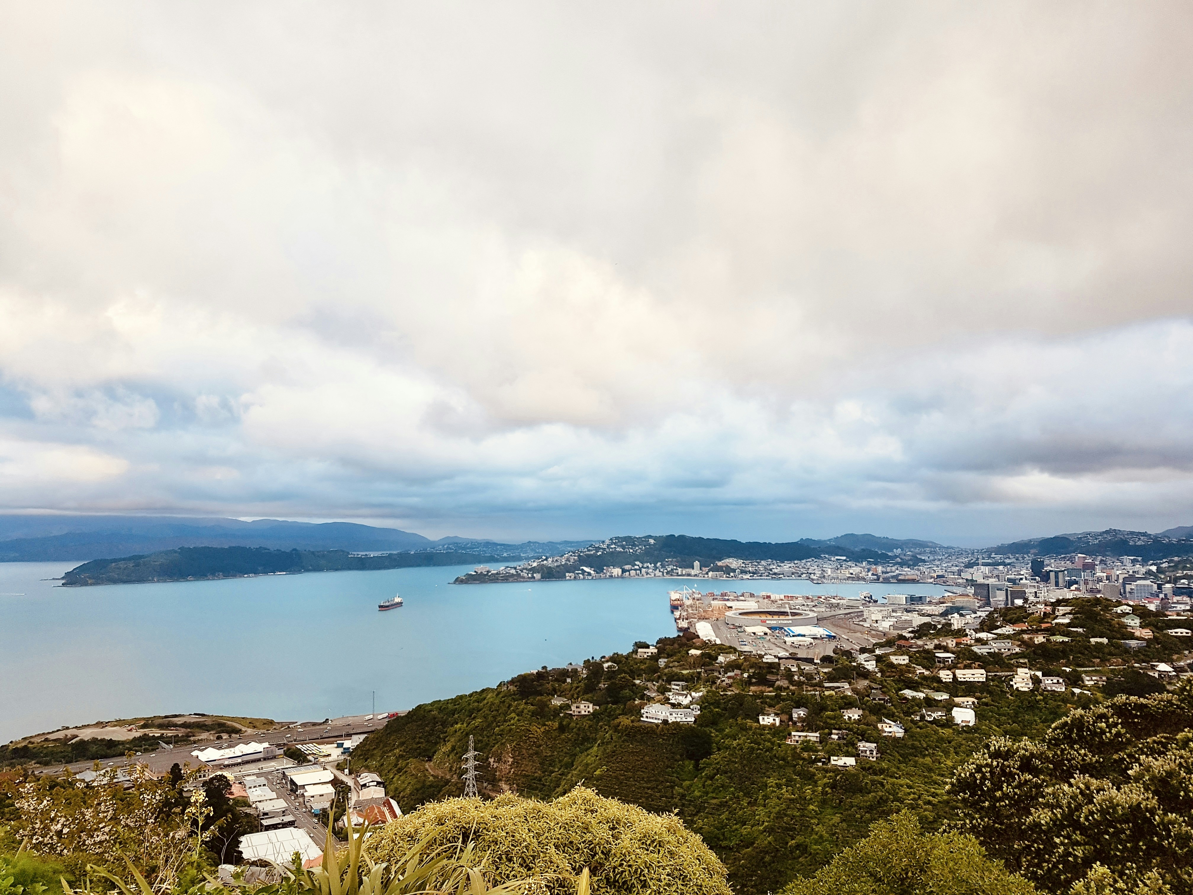 Coastal Panorama: Island harbor and hillside town under a cloudy sky