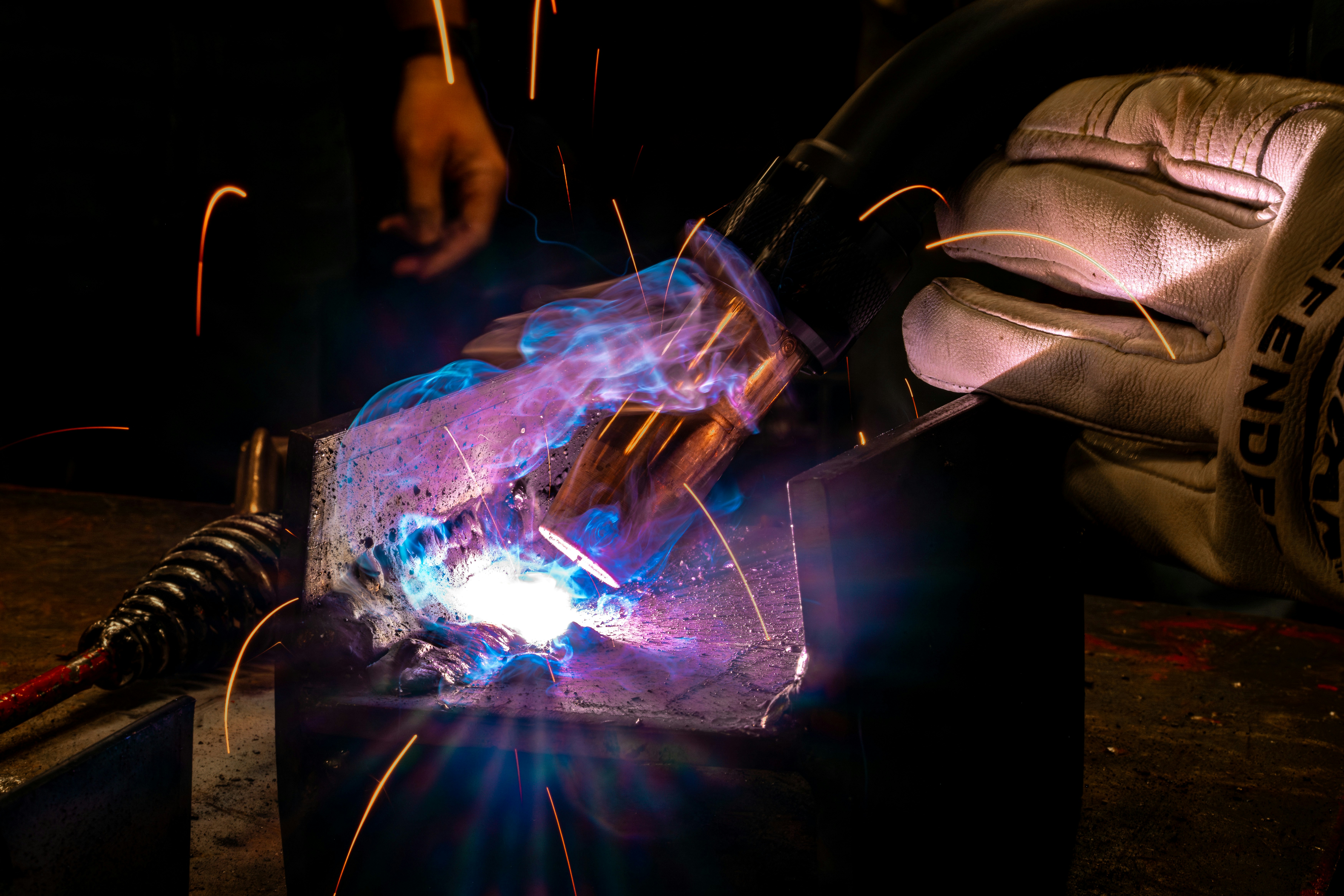 Bright welding sparks illuminate skilled metalwork during a close-up view of industrial craftsmanship.
