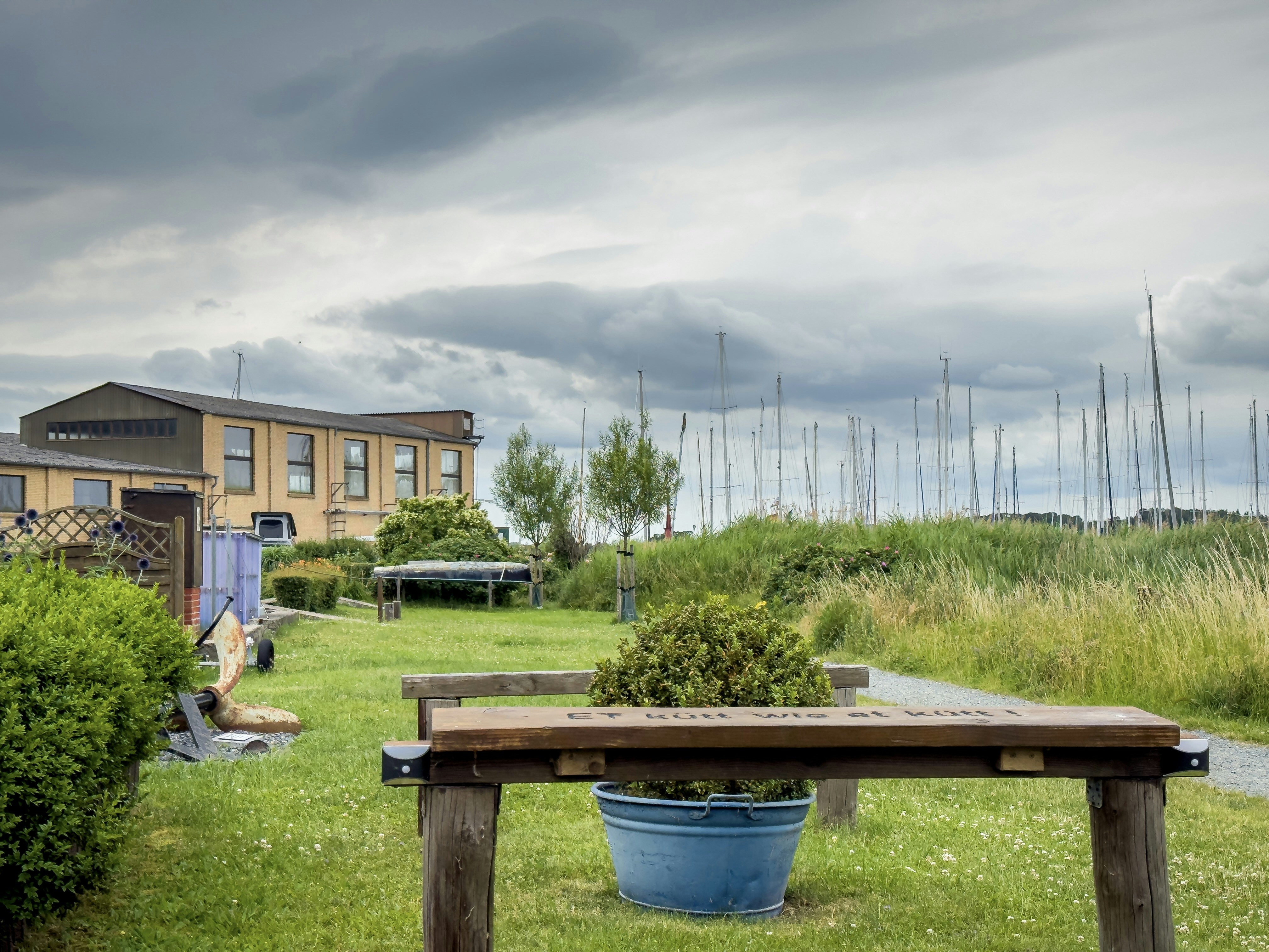 Wooden table in a seaside park with a blue pail and distant marina