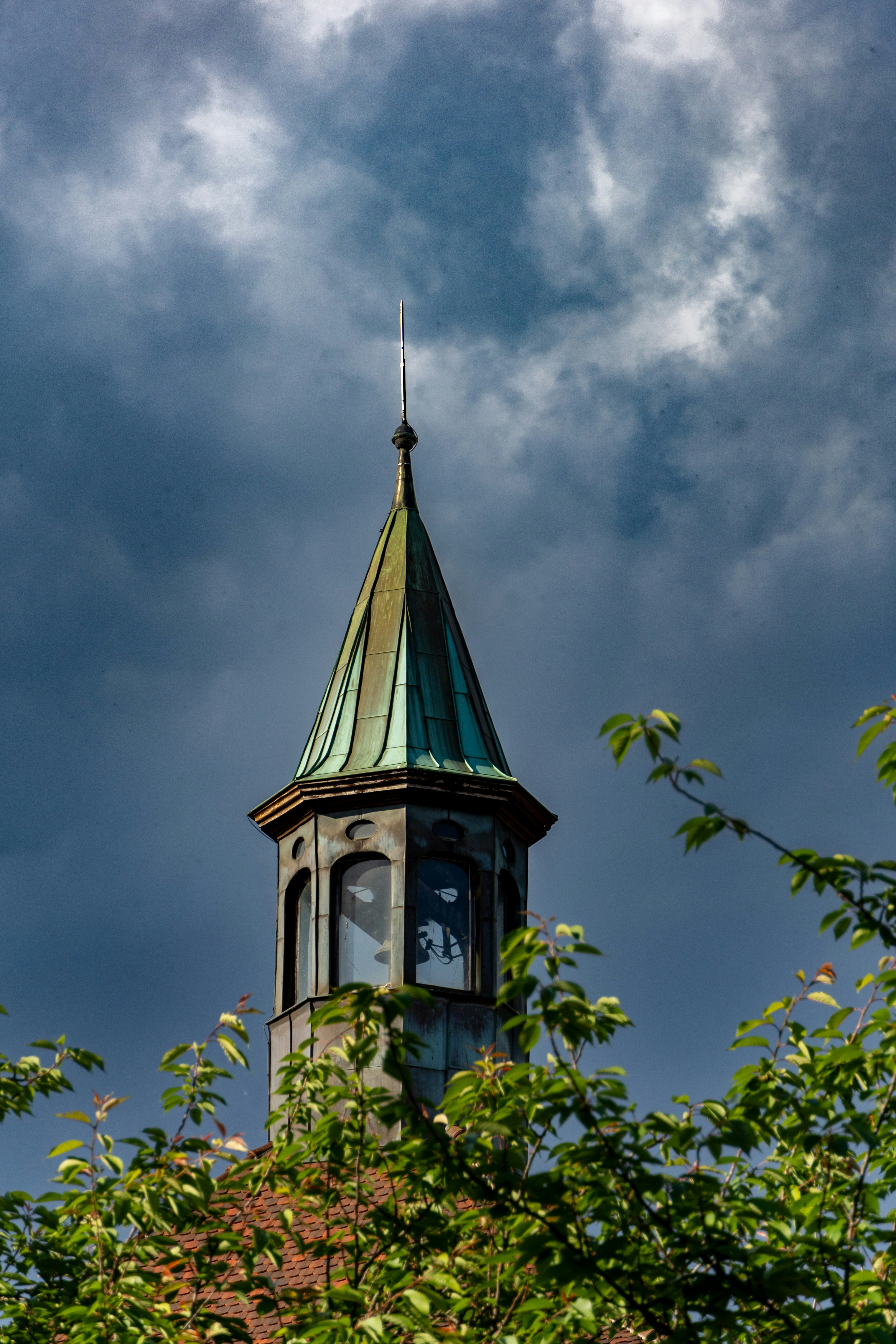 Steeple Above Greenery: A Towering Clock-Tower Crown Piercing the Sky