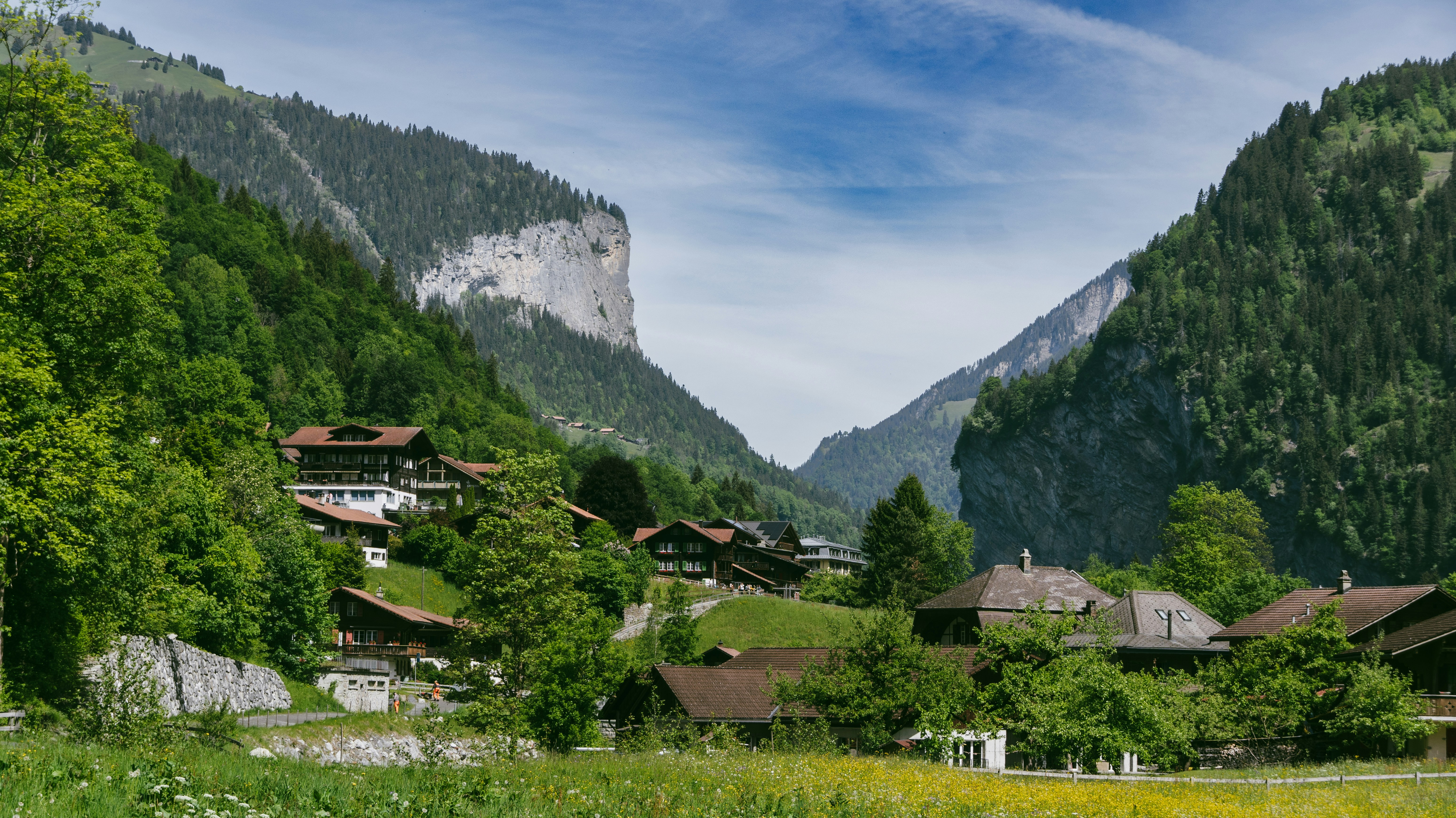 Mountain Village Mirage: Green Slopes and Cliffside Homes Framed by V-Shaped Valley