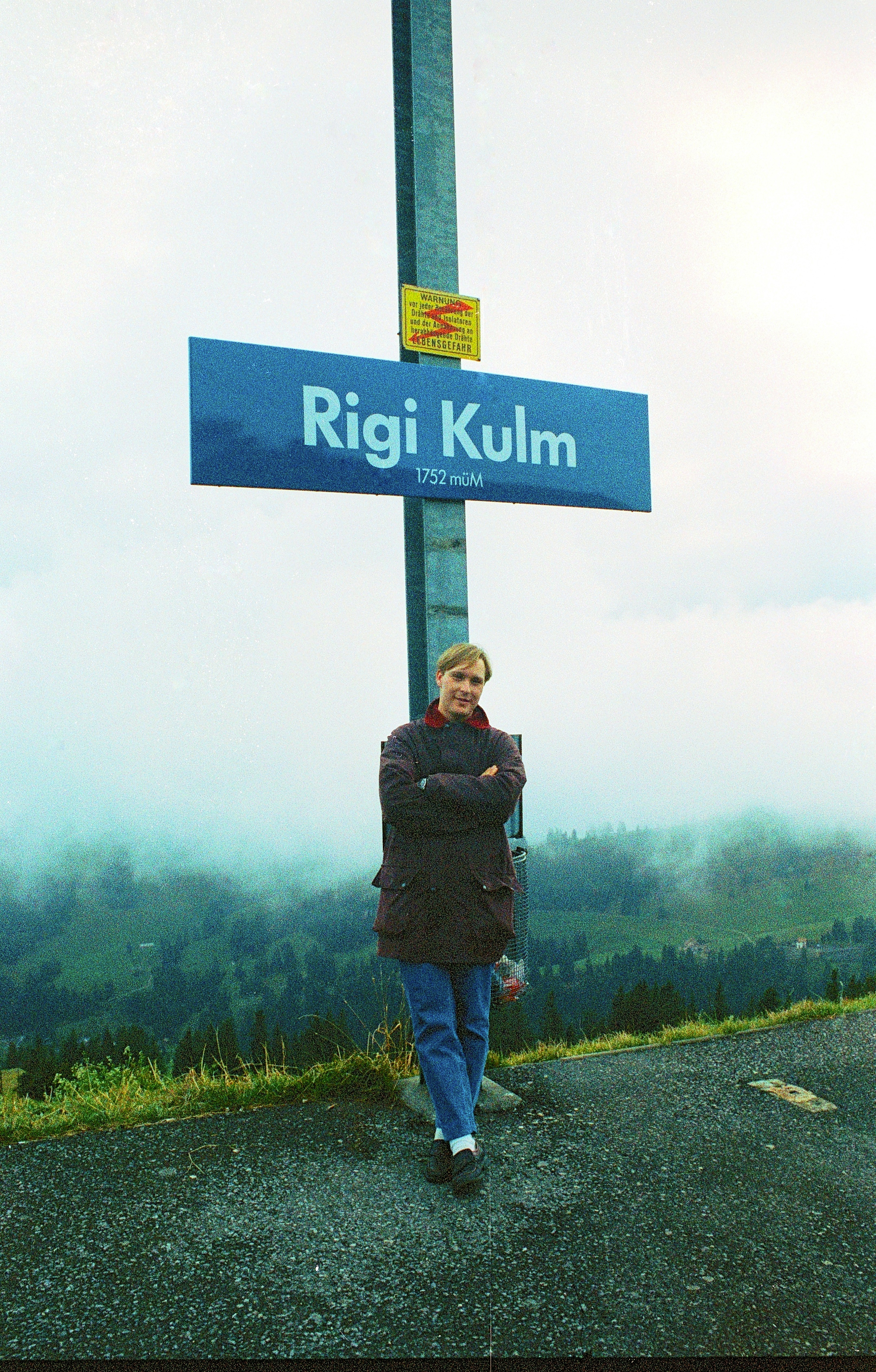 Graded Signpost and Figure at a Misty Clifftop