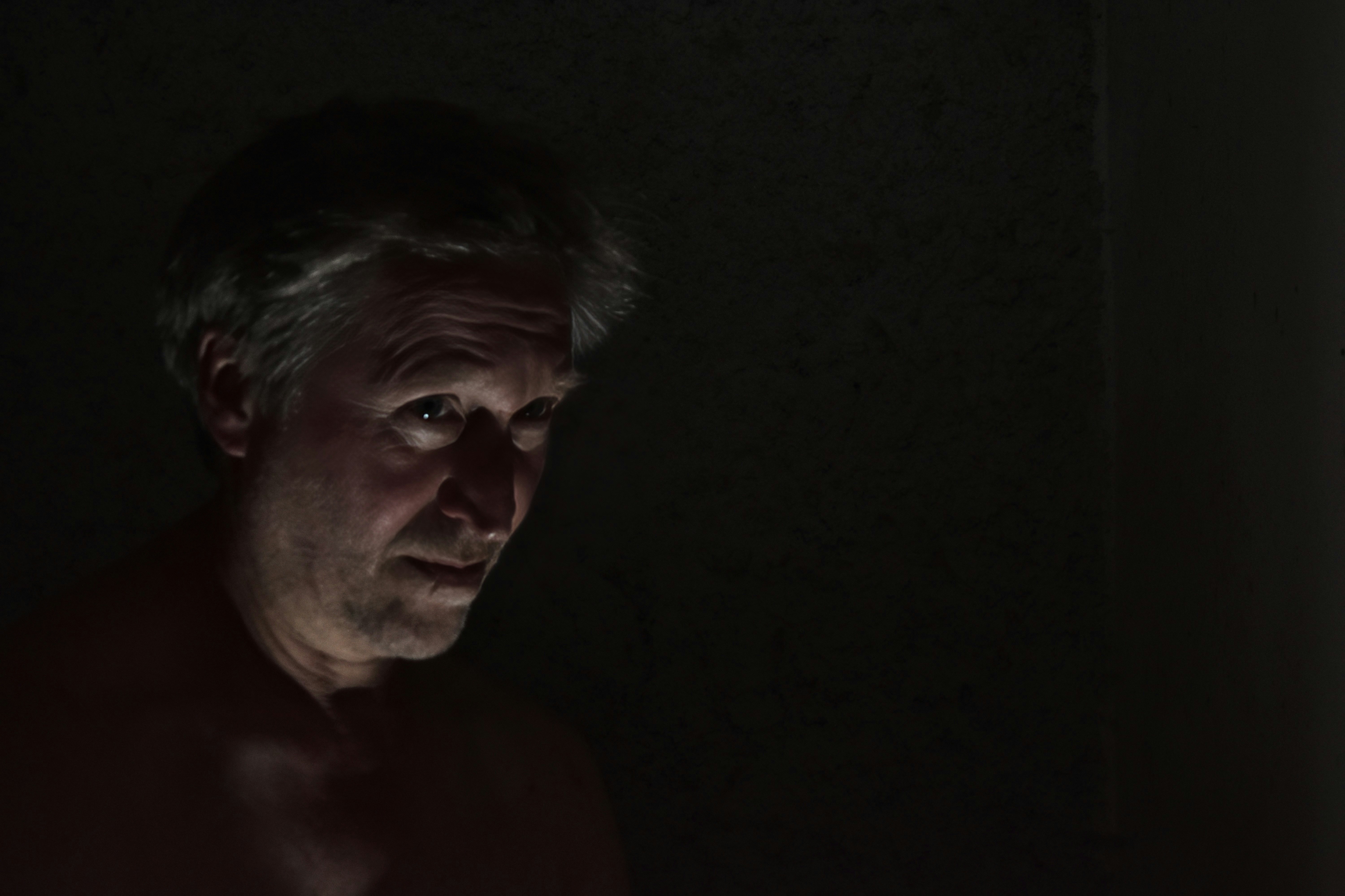 Portrait in Shadows: A Weathered Gaze Emerges from the Dark
