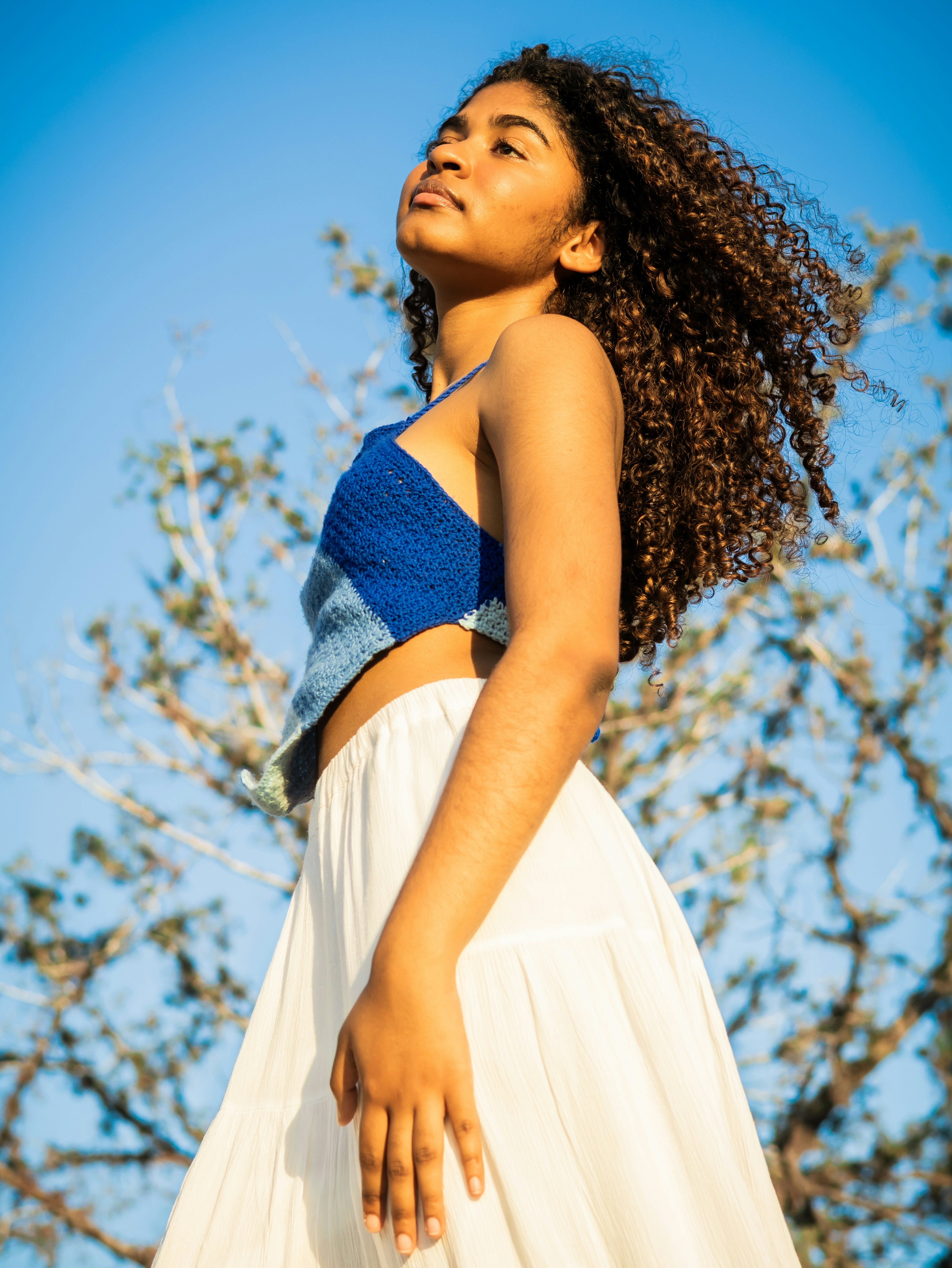 Sunny ascent: portrait of a girl in blue knit top against a bright sky