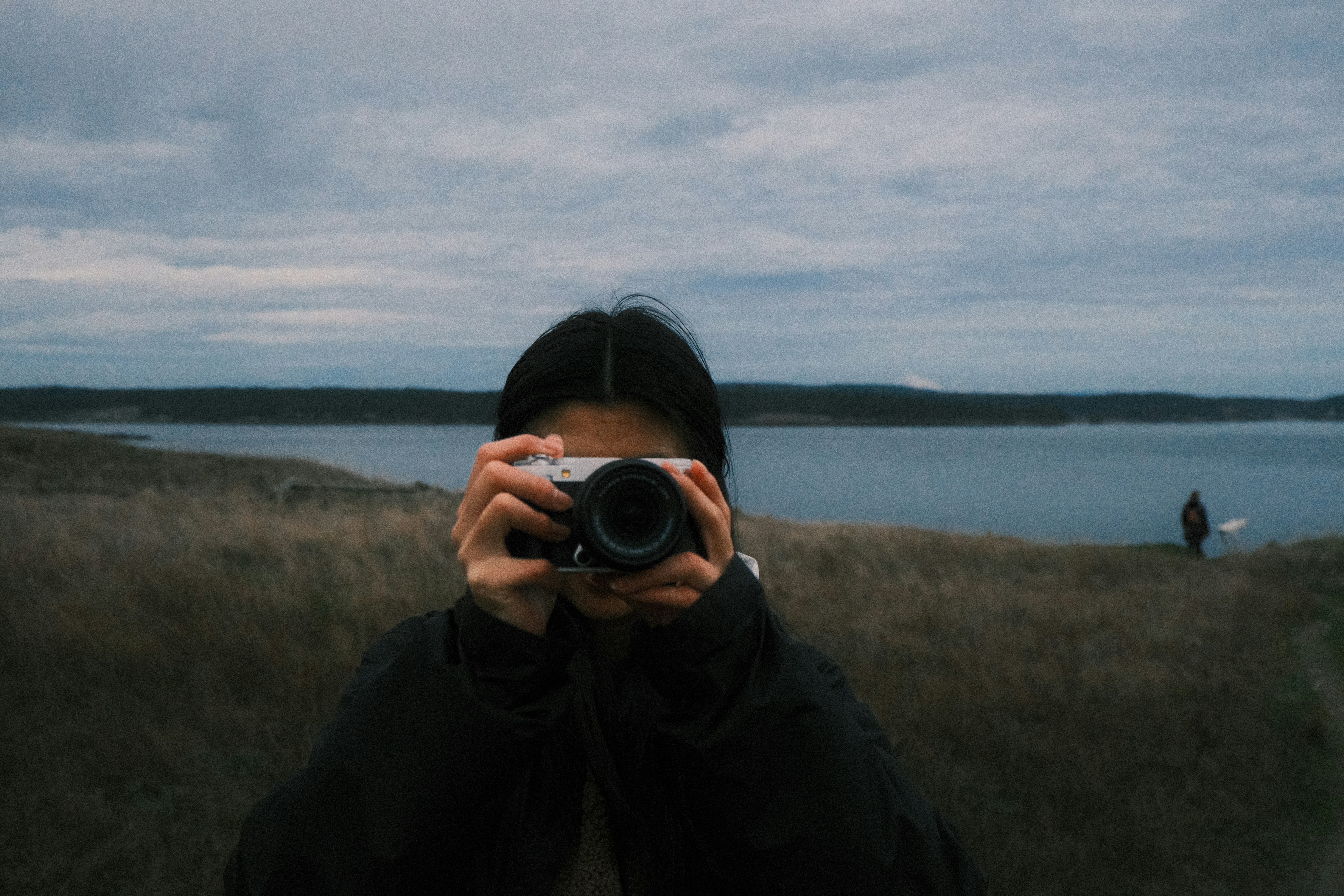Quiet Moment: The Photographer Framed Against a Distant Shore