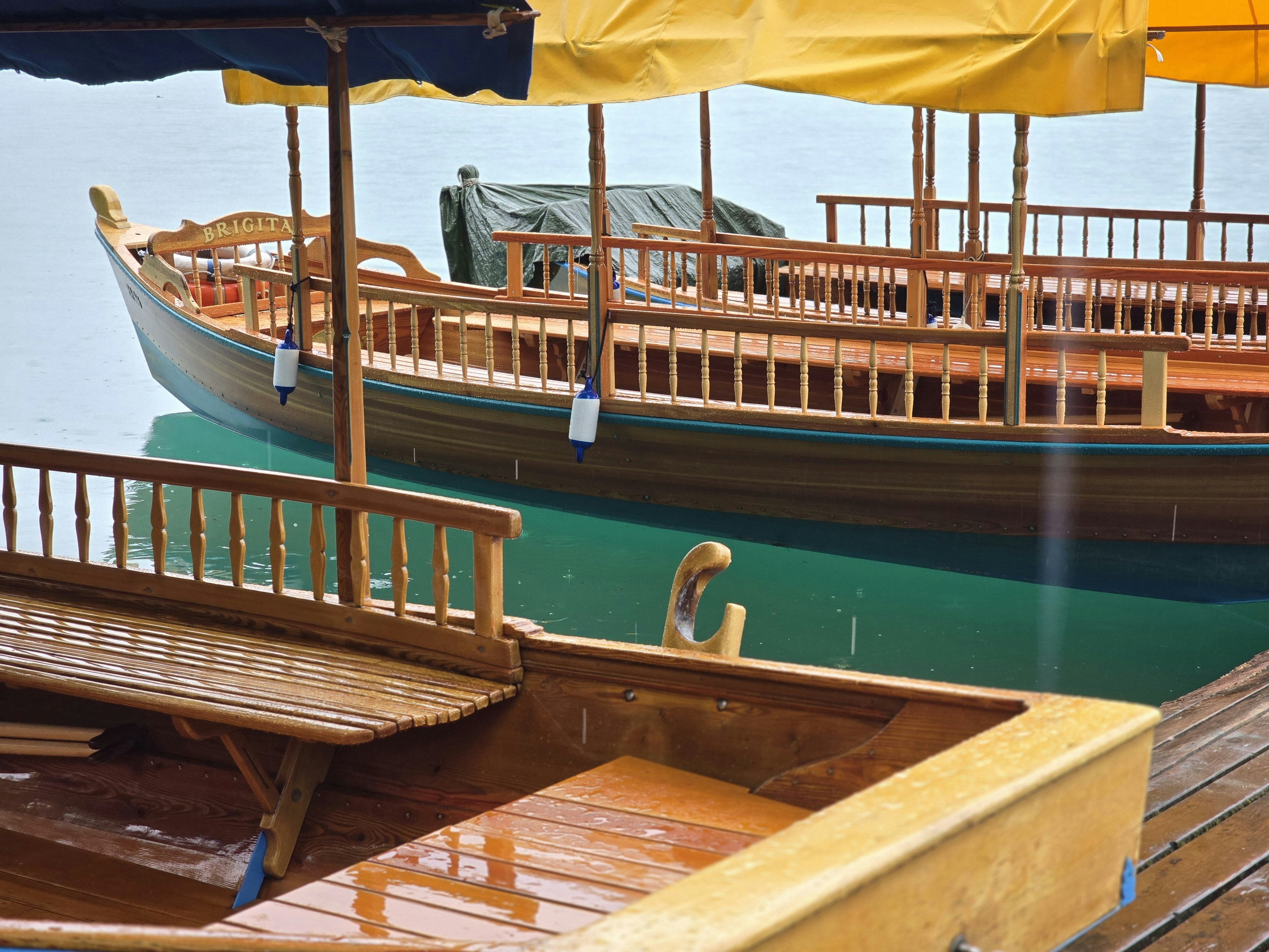 Boat deck in turquoise water: sunlit teak and shade beneath colorful canopies