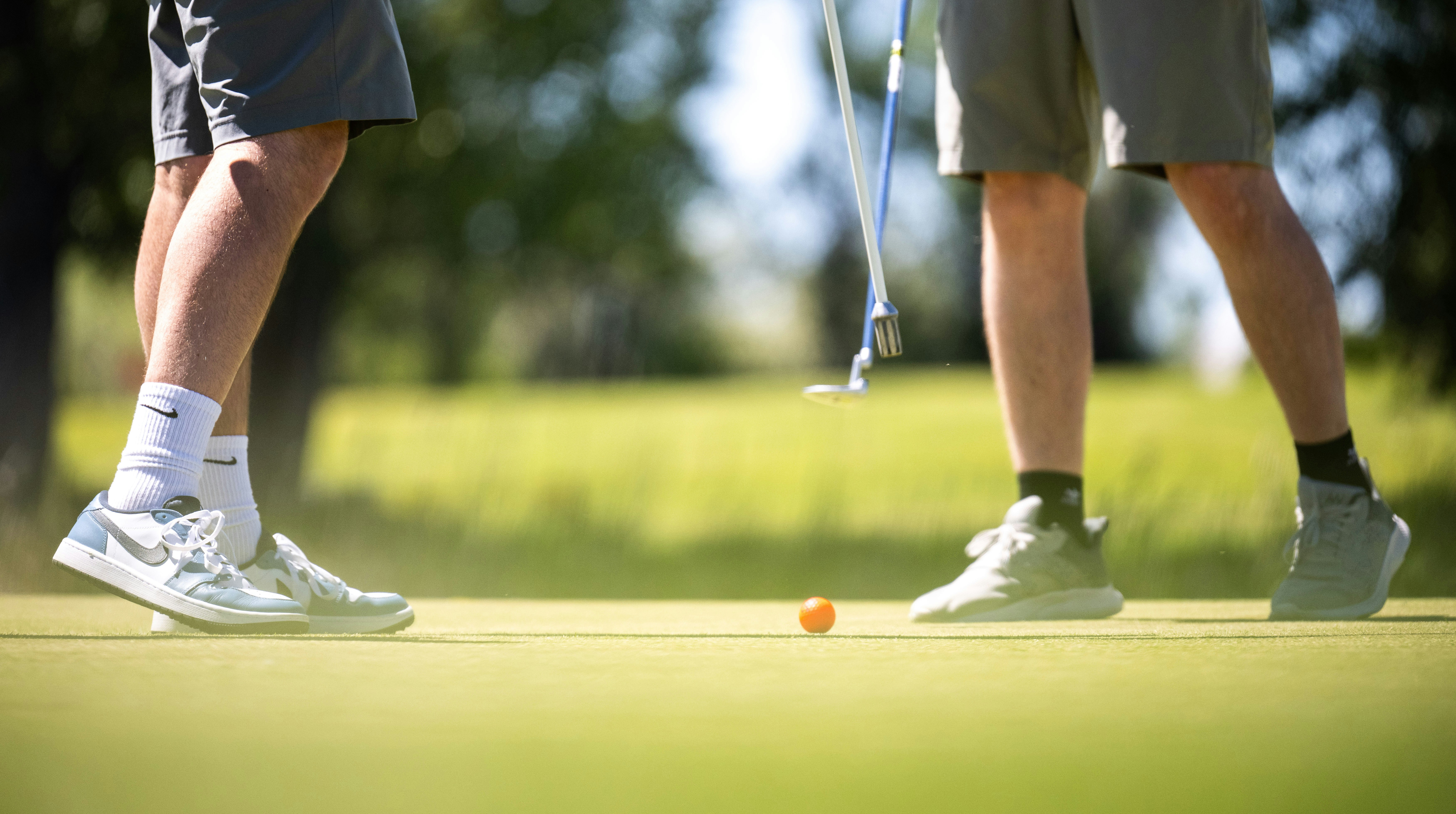 Two Golfers in a Sunny Green: Close Proximity to the Putter Moment