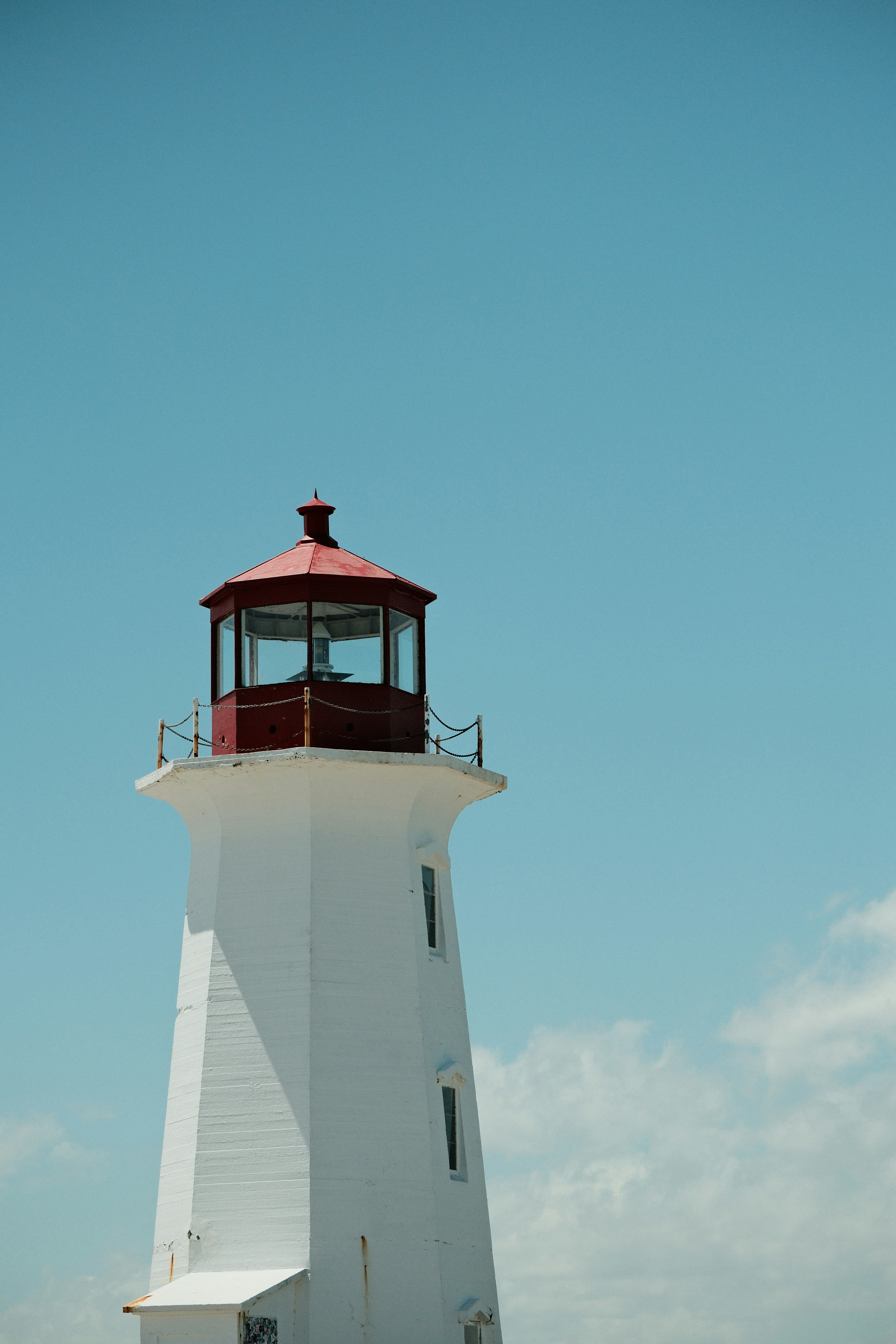 Beacon of Steel and Sky: A White Lighthouse Reaching Toward a Clear Horizon