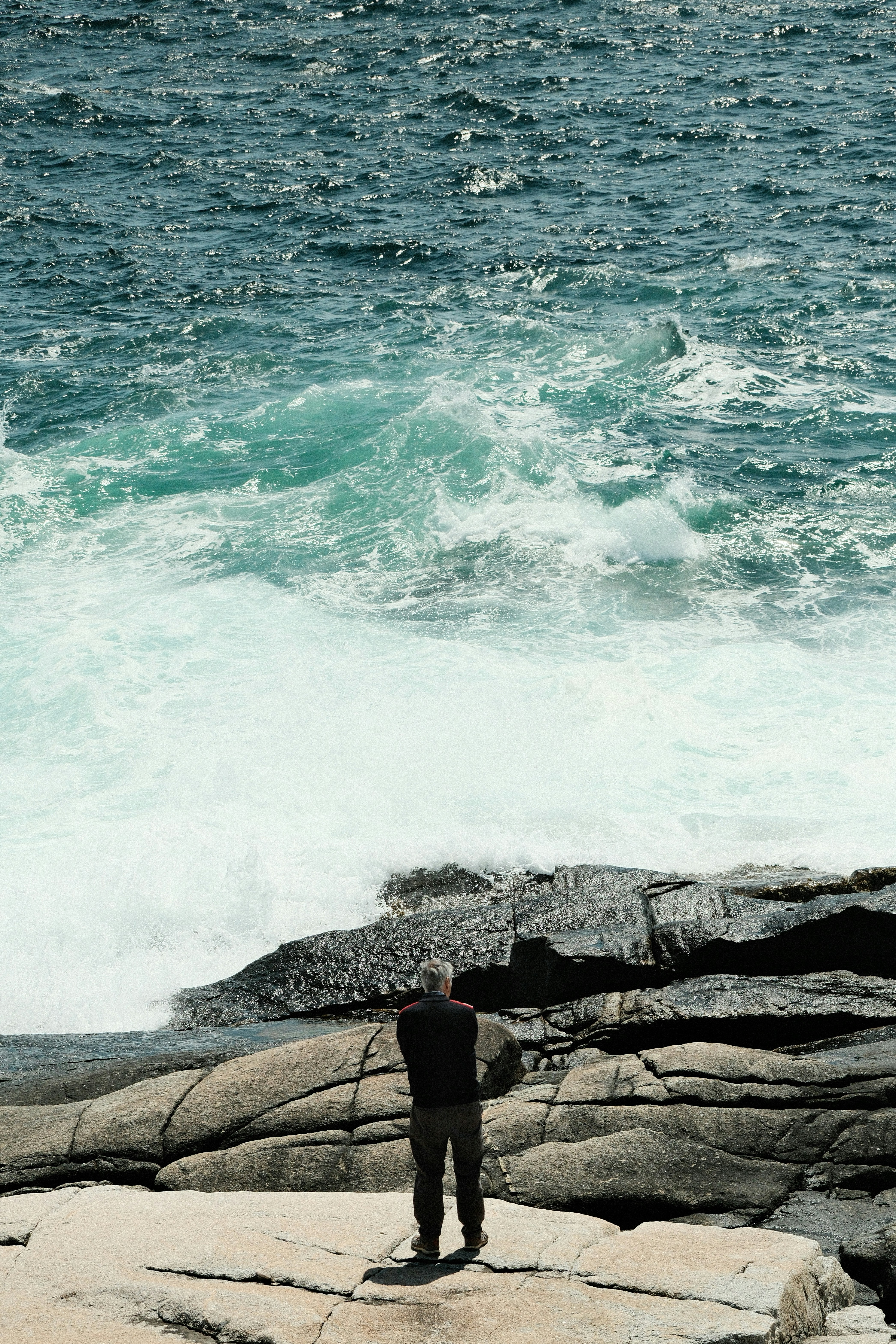 Rugged shoreline Portrait: A lone observer amid crashing surf