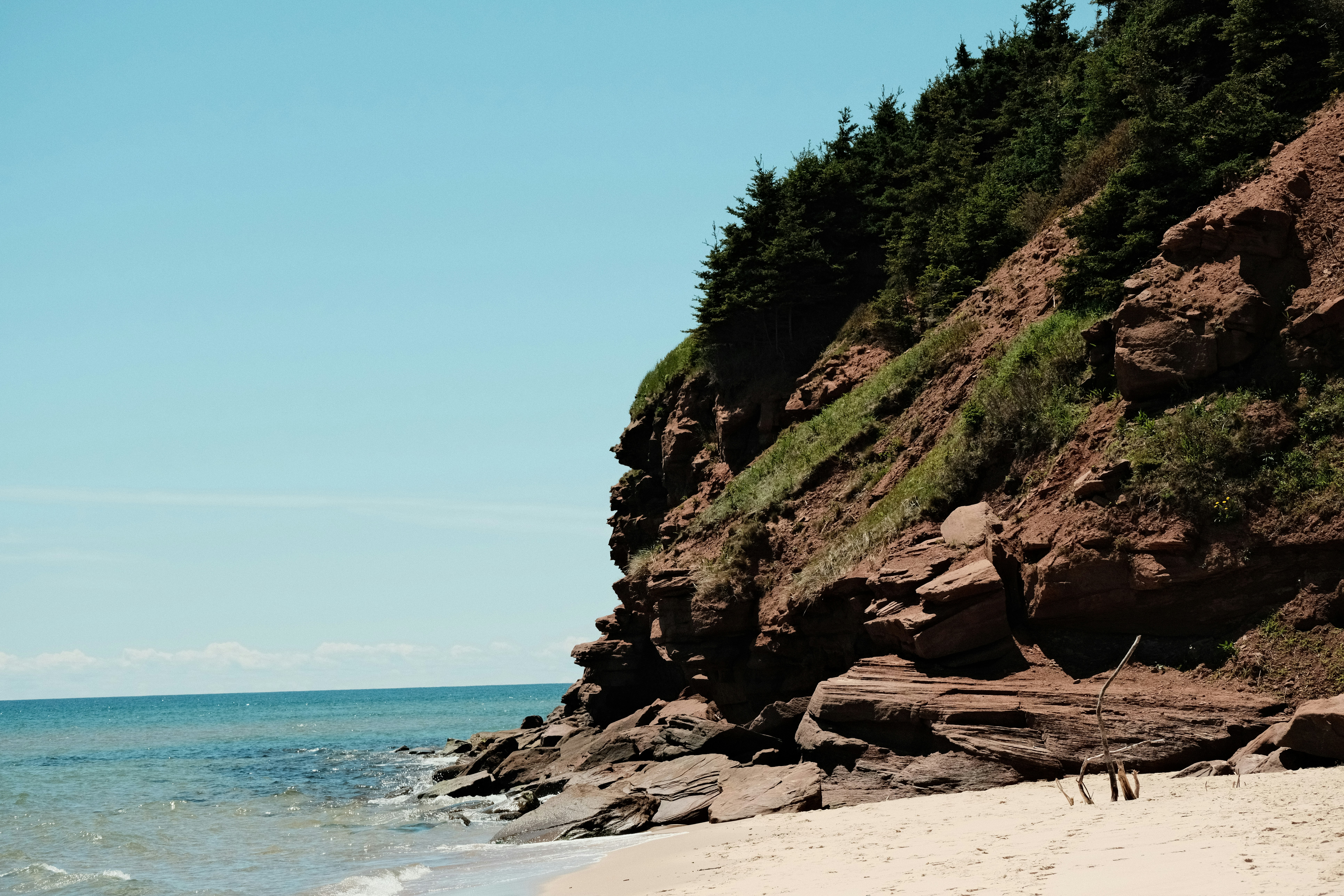 Sea Cliff Serenade: Sunlit Sand and Red Rock at Dune Edge