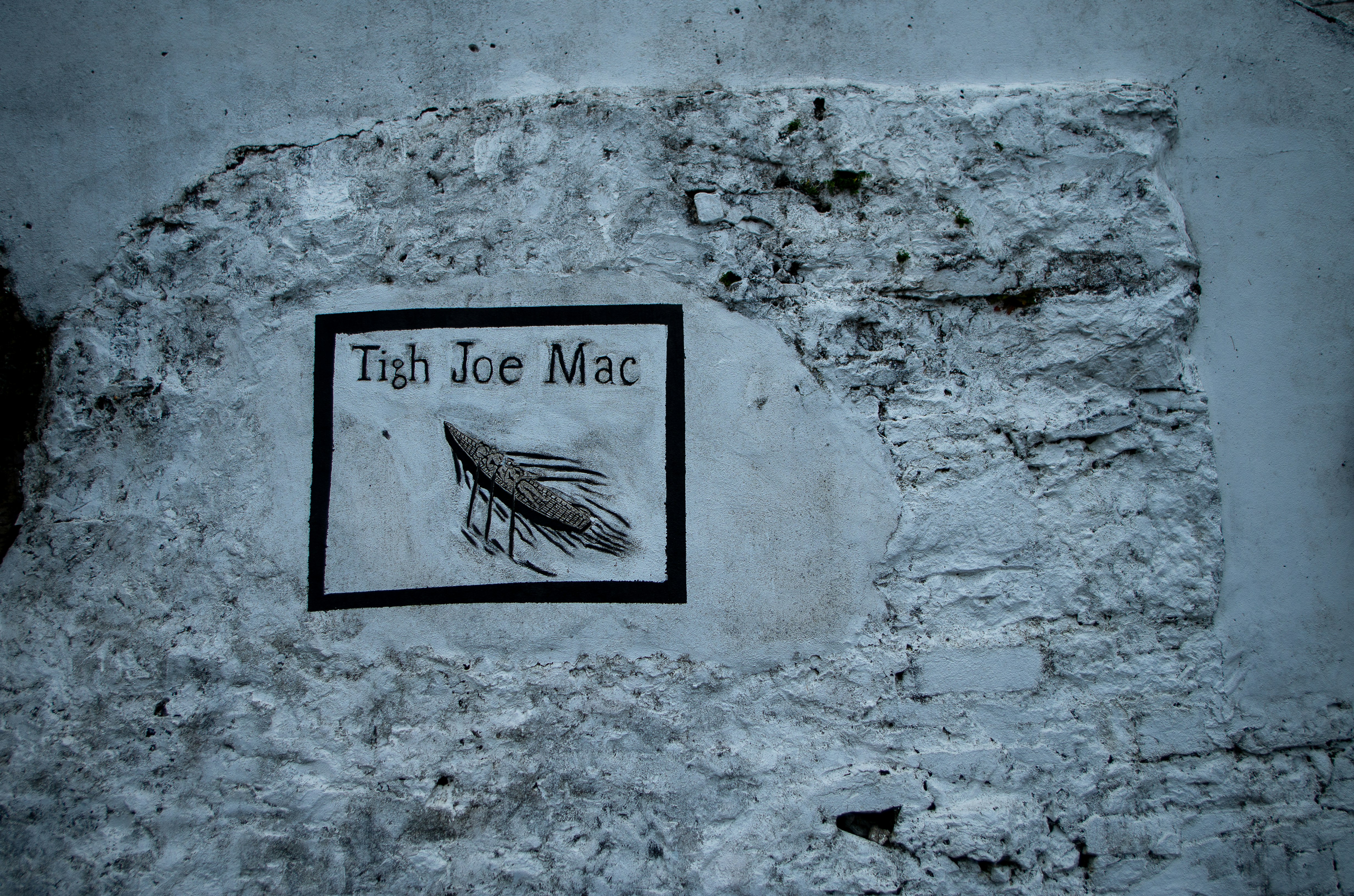 Sign of Tigh Joe Mac: A Weathered Sketch on a Crumbling Wall