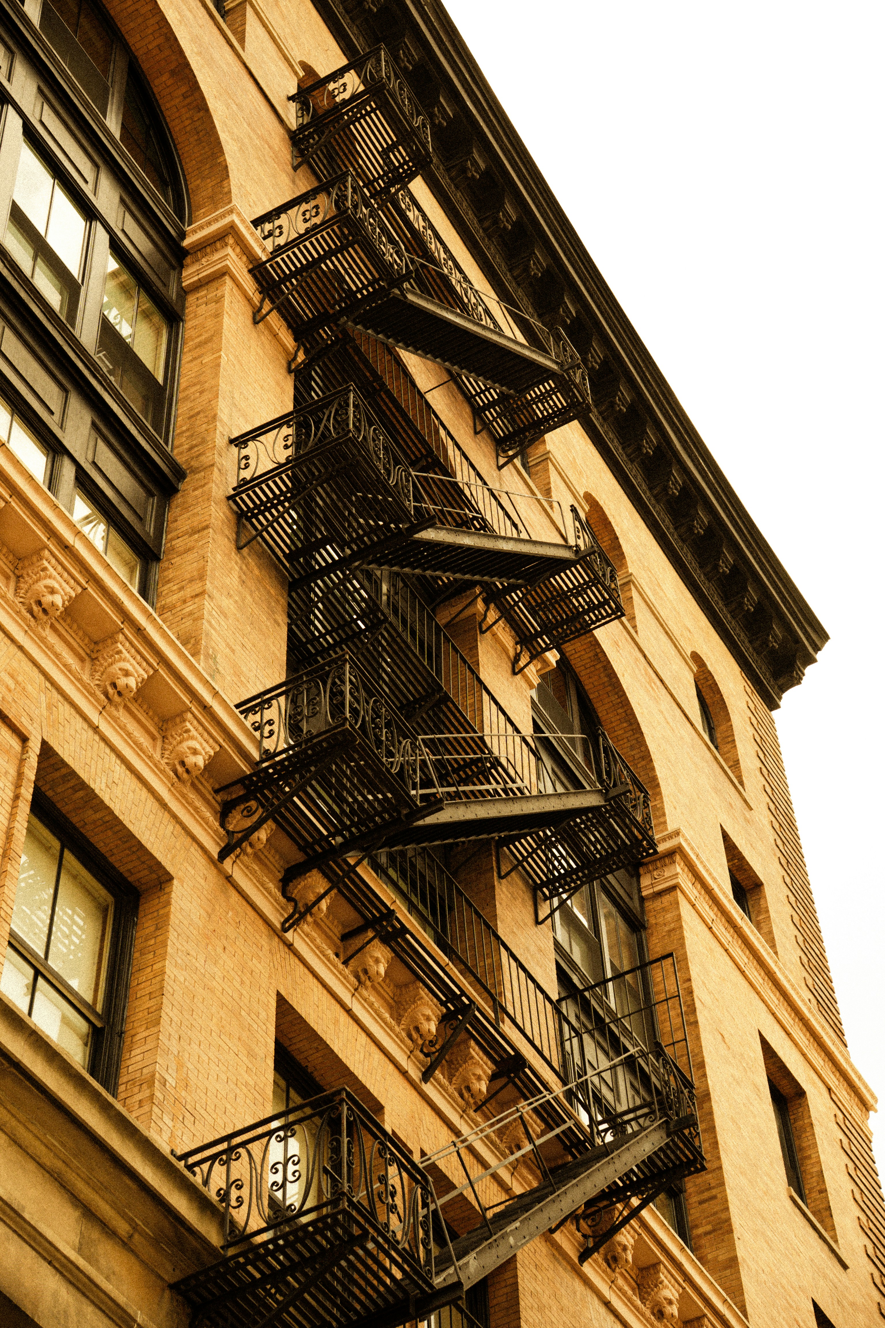Fire escape diagonals on a sunlit brick façade