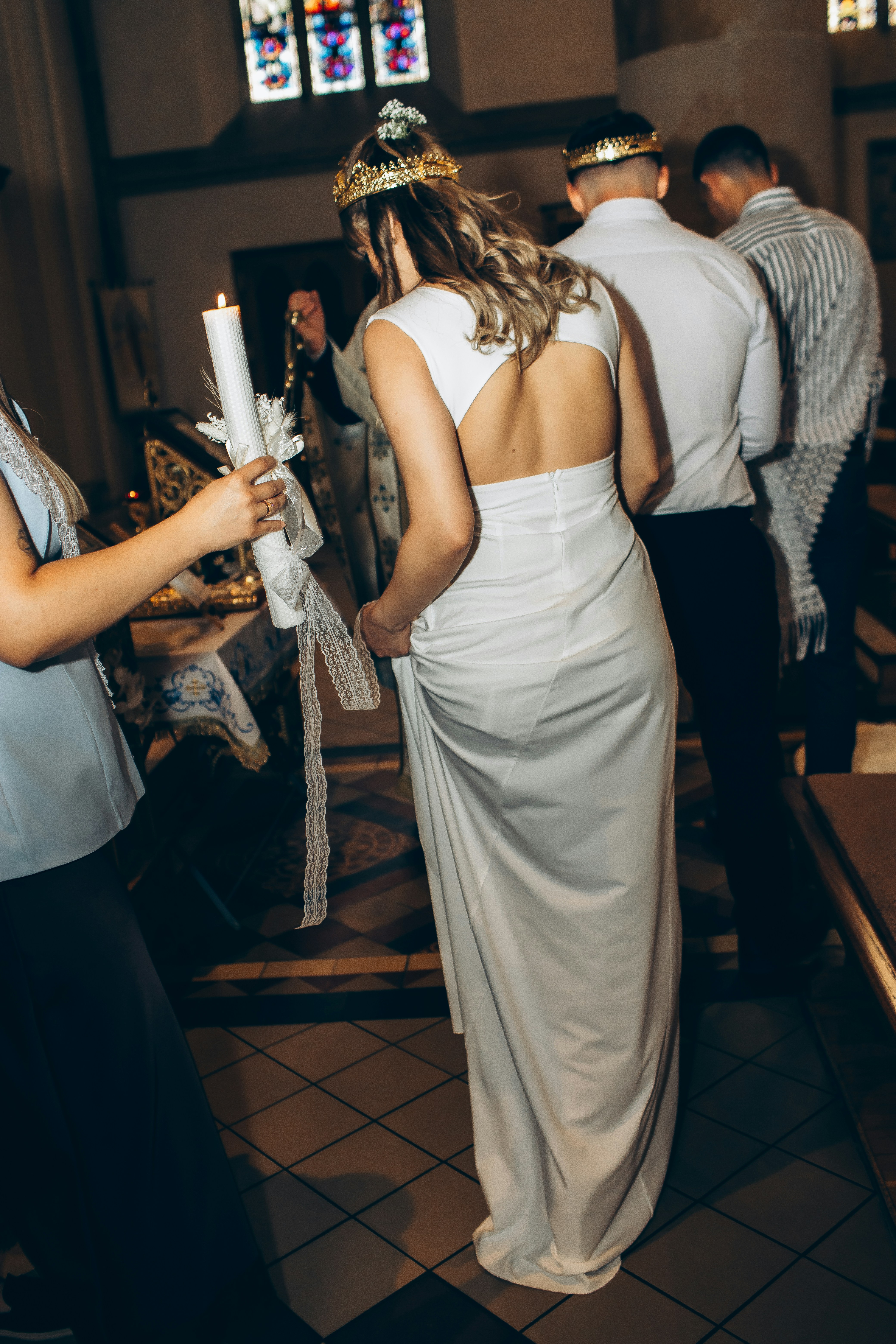 White-gowned moment: a ceremonial kiss of light in stained-glass shadows