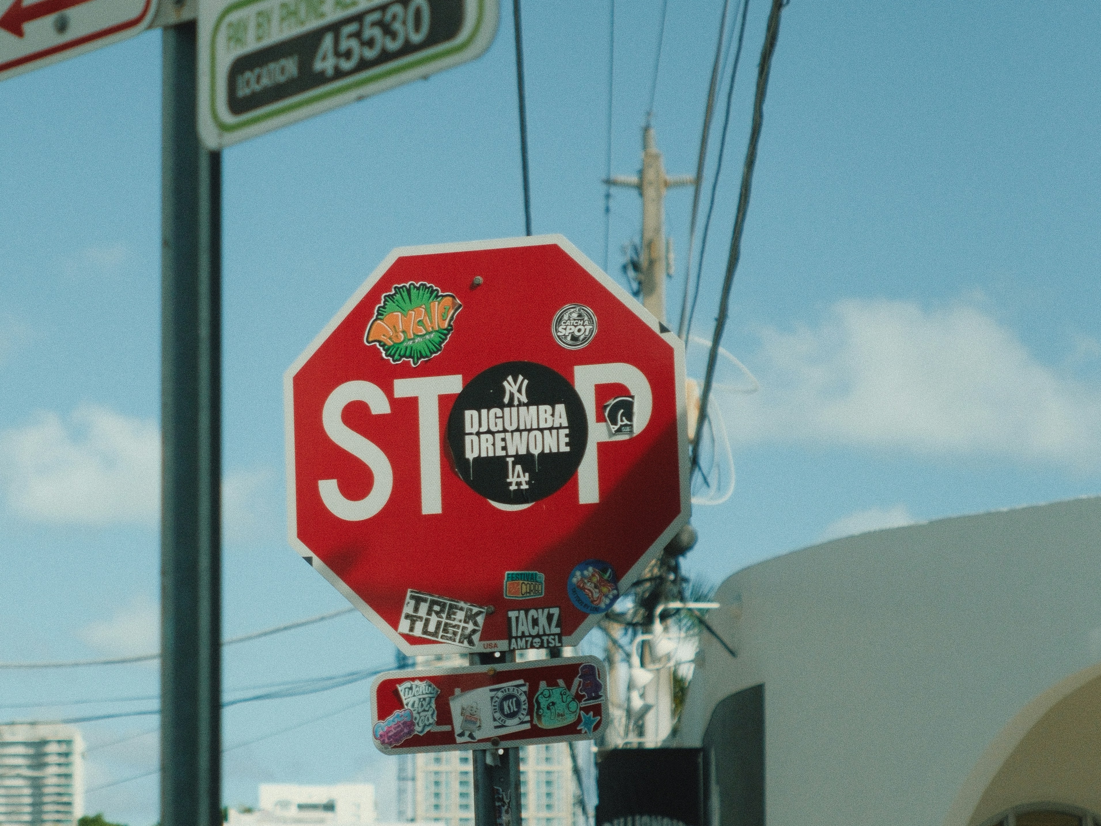 Layered Stop Sign: Stickered Octagon Against Urban Sky
