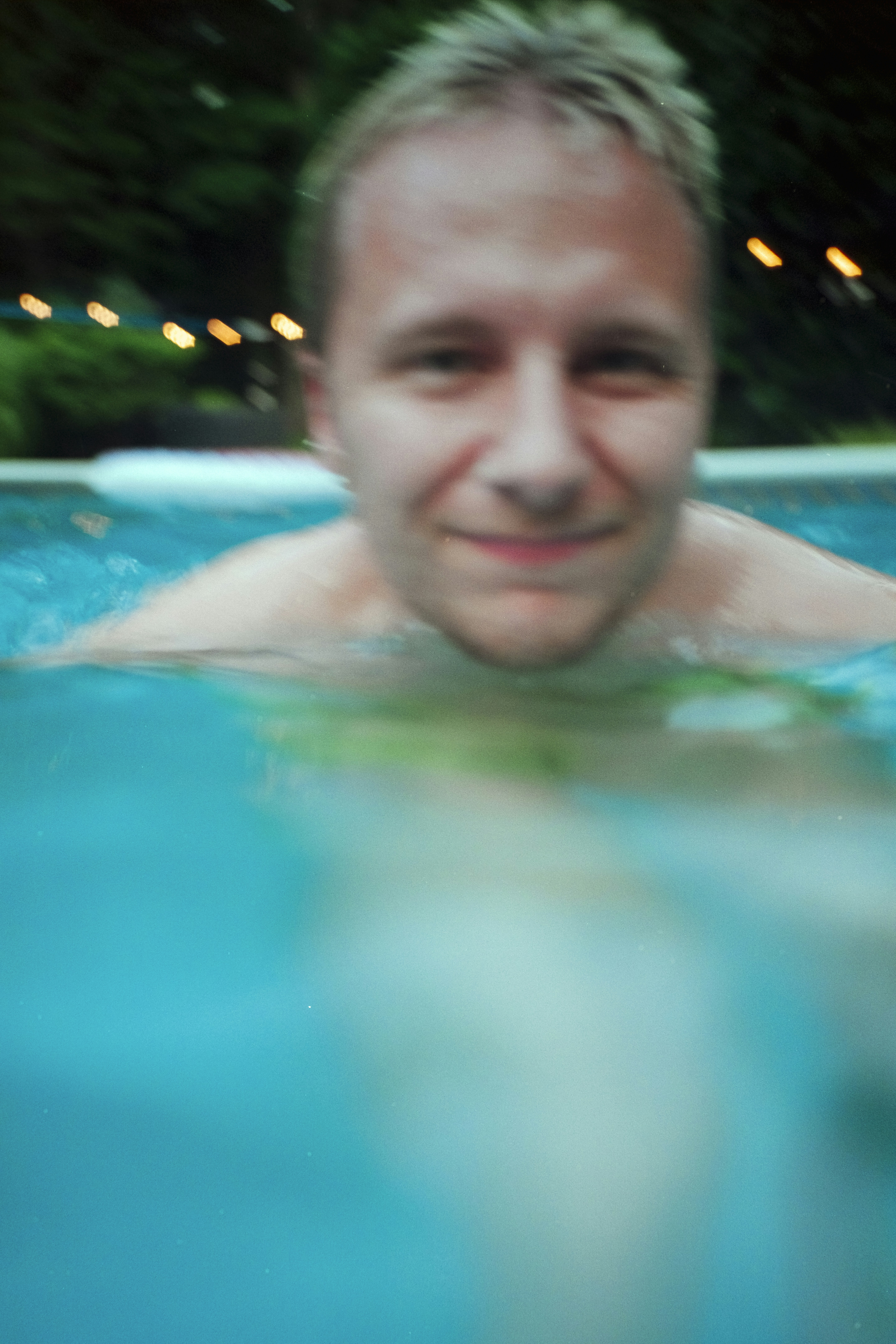 Poolside Blur: A Close-Up of a Smiling Face Emerging from Water