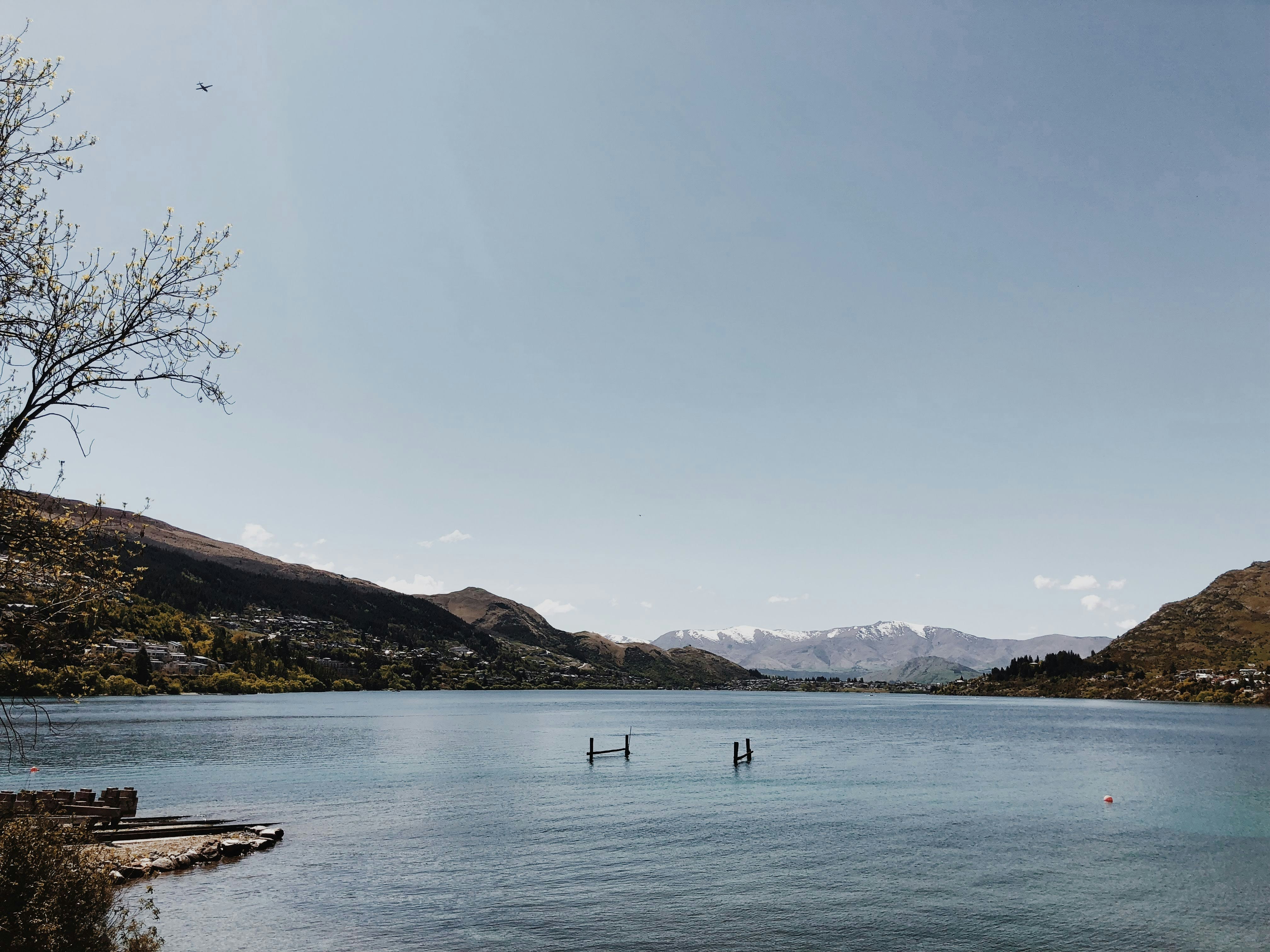 Calm lake under a clear sky with distant snow-capped mountains