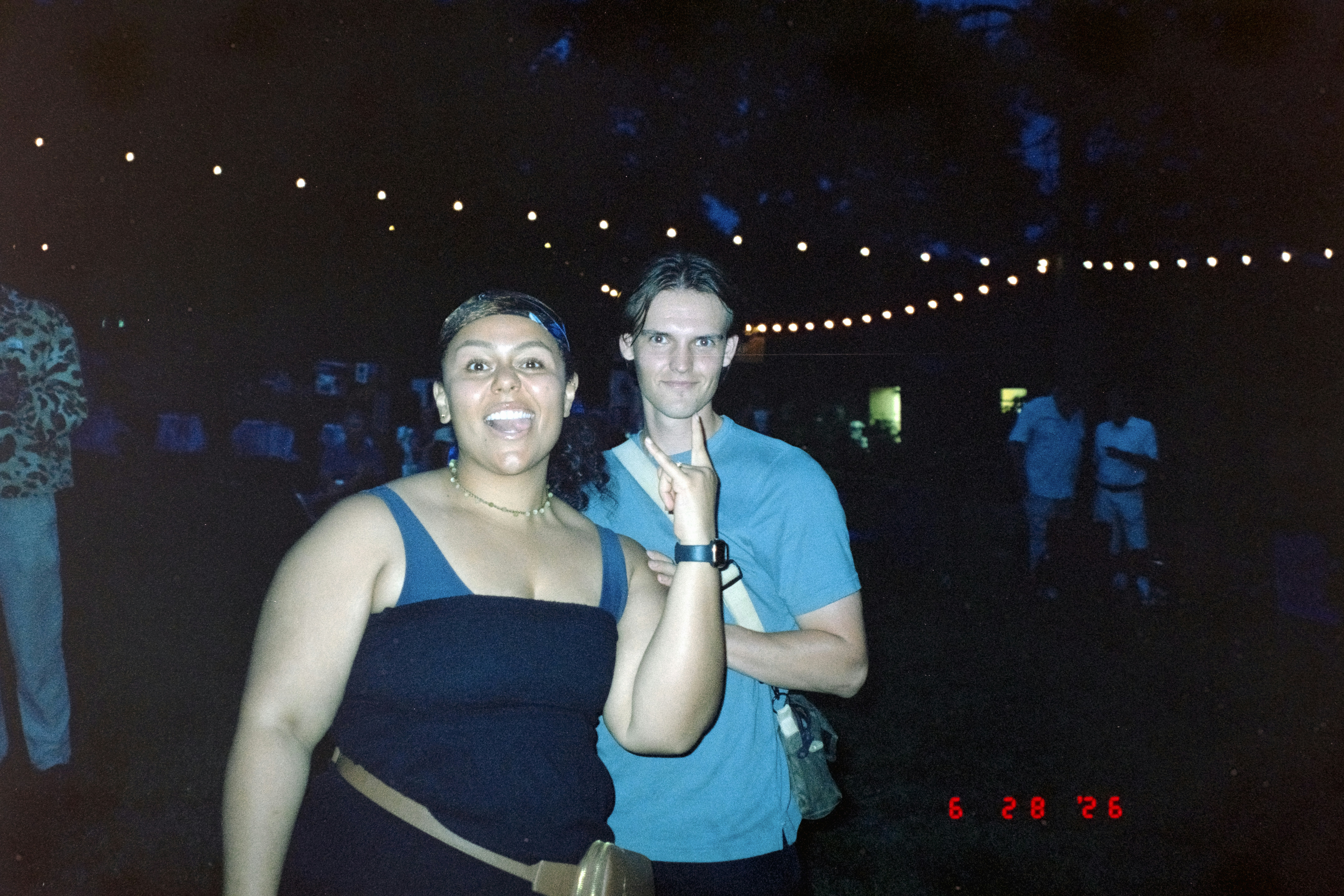 Nighttime festival selfie with string lights and a playful pose