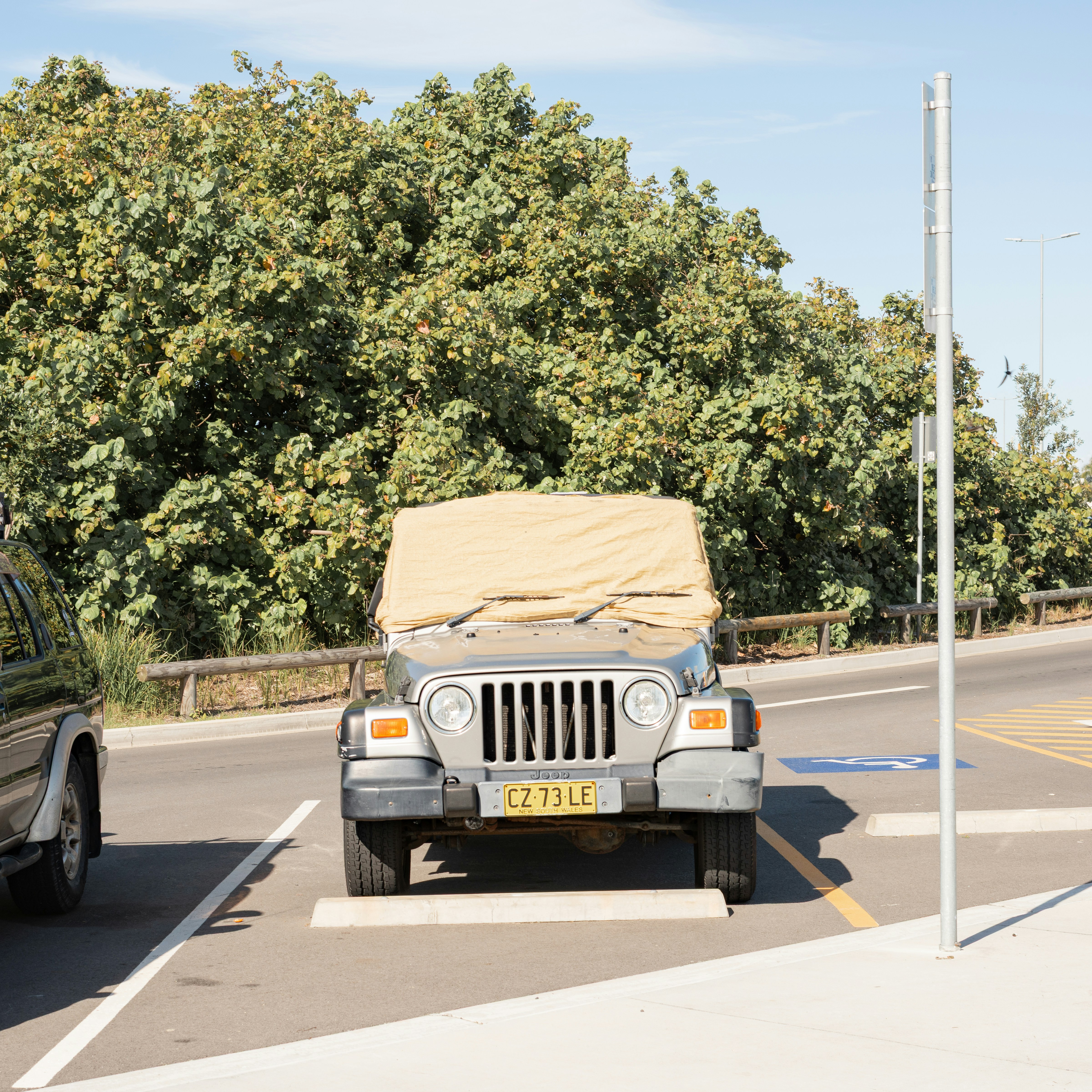 Sunlit Jeep in Parking Lot with Folded Canvas Top