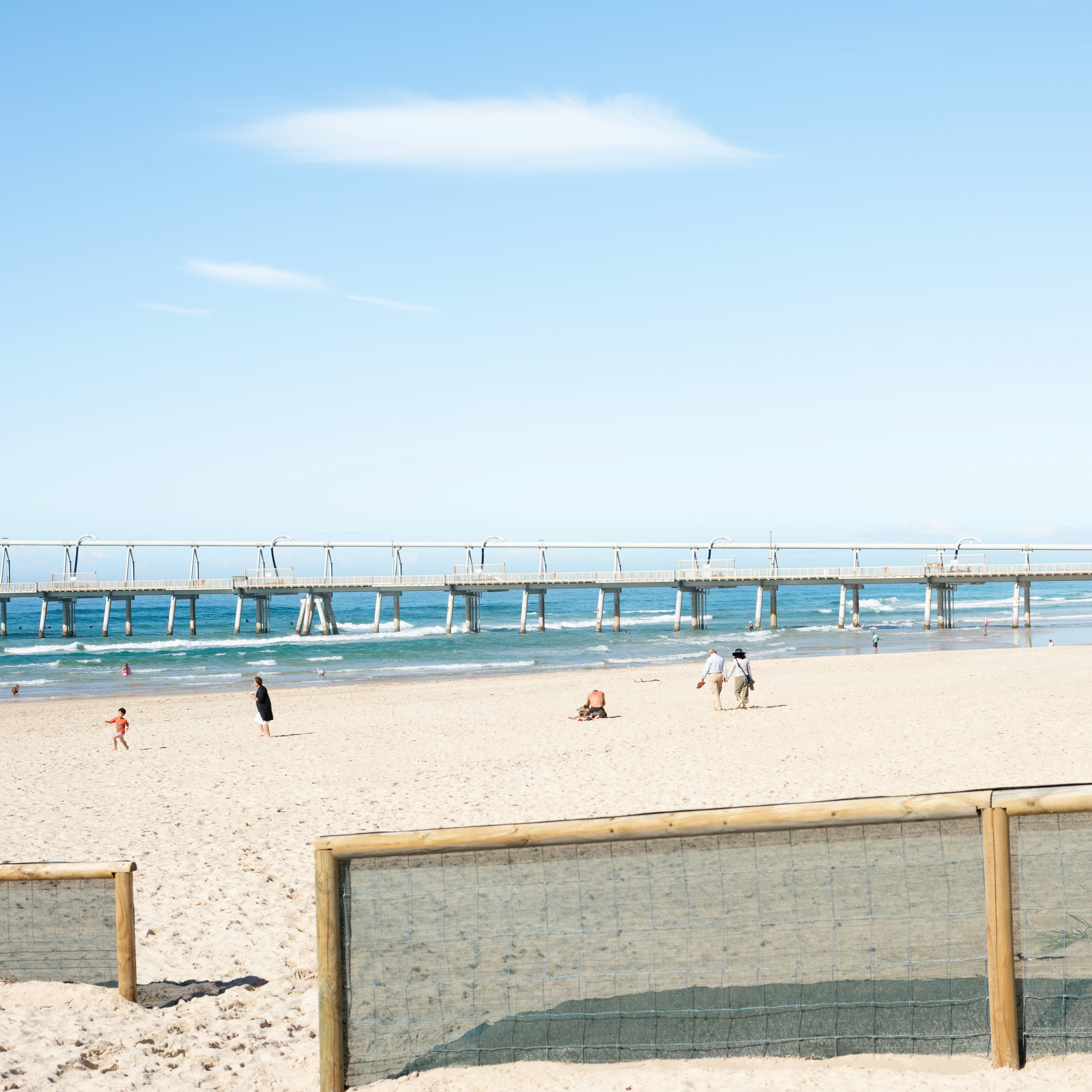 Shoreline Echo: a sunlit beach with a weathered pier