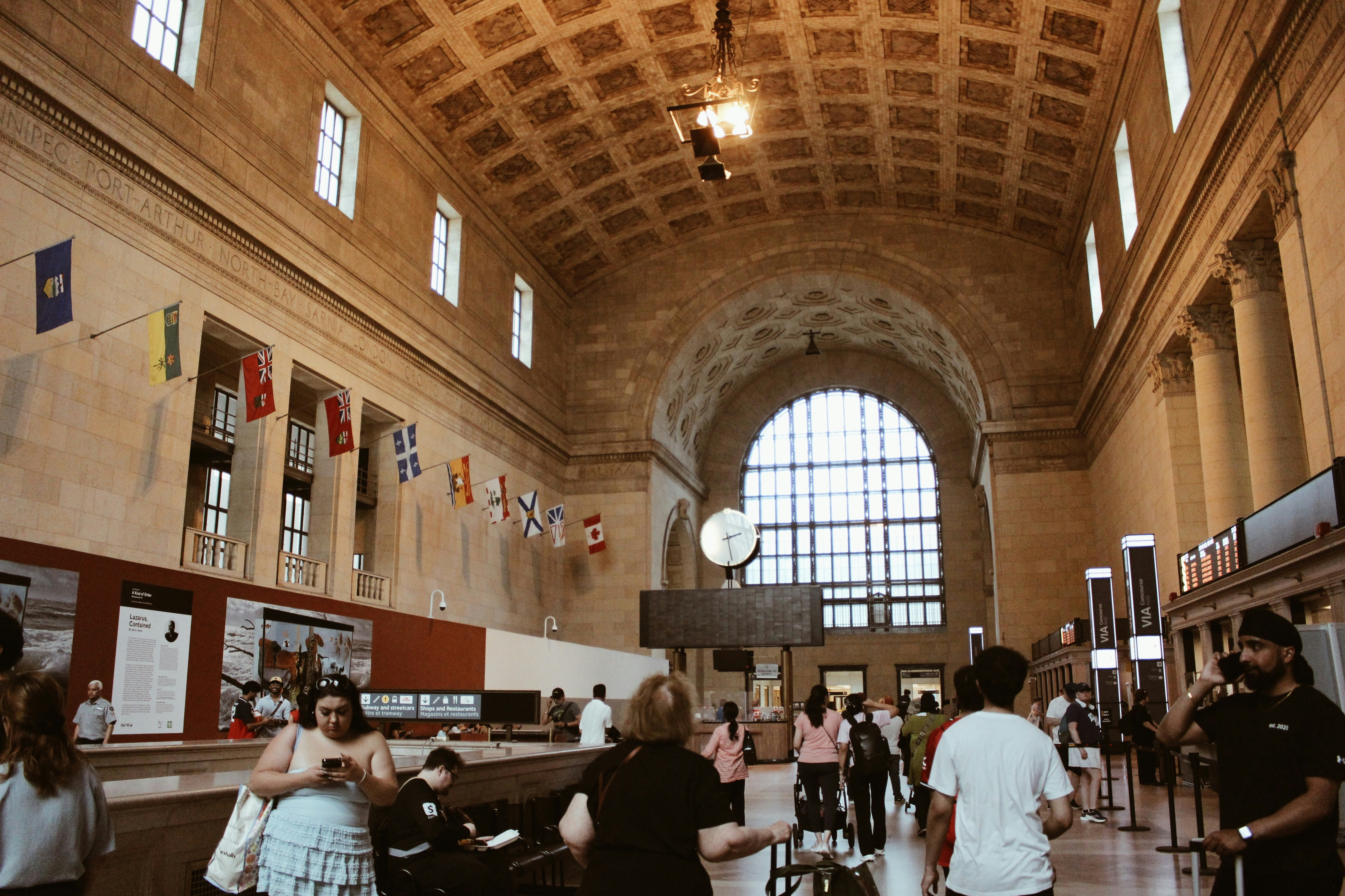 Grand Hall of Flags and Arched Window: People Explore a Historic Exhibition