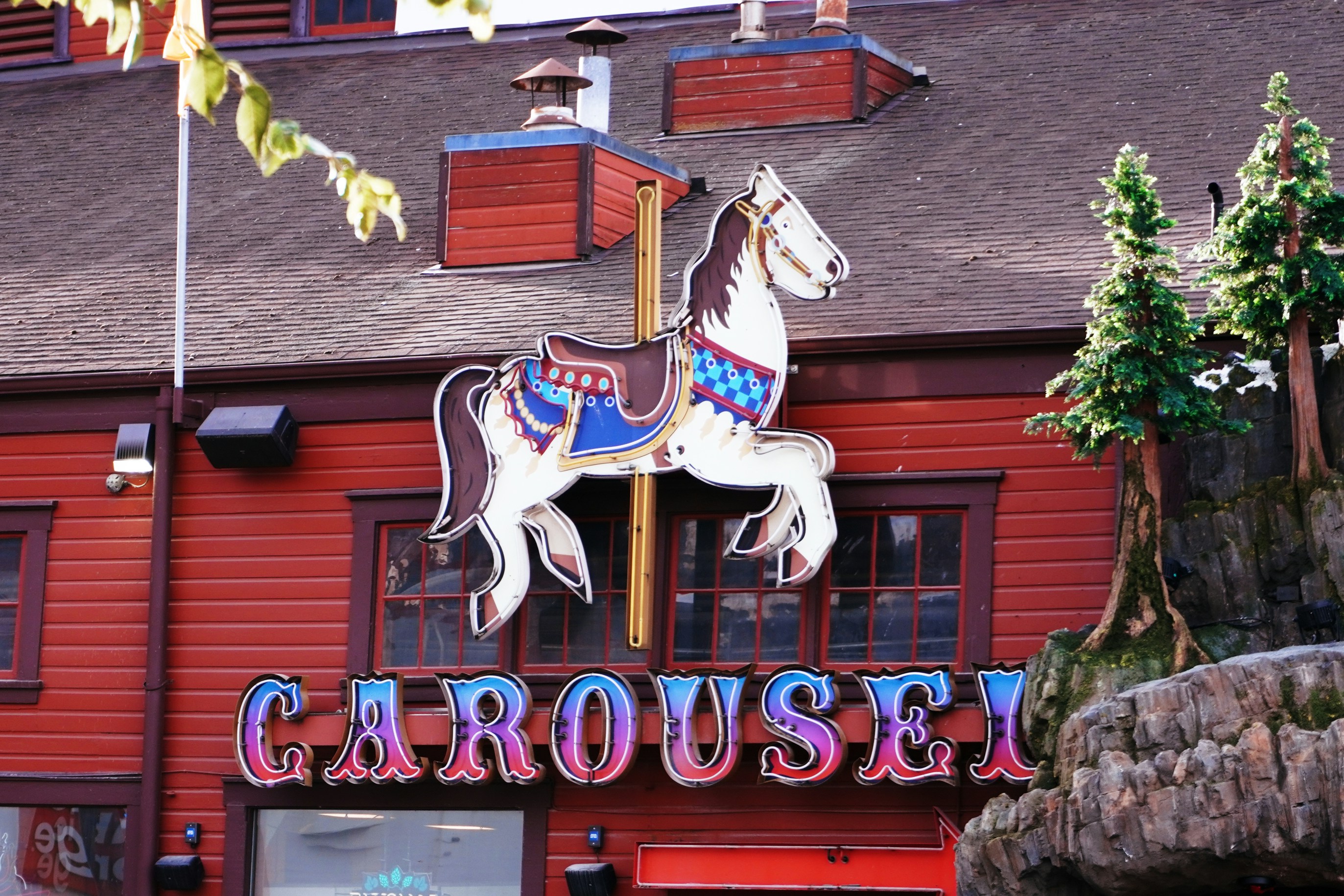 Carousel Horse Above a Red Facade: Neon Sign and Rock Terrace
