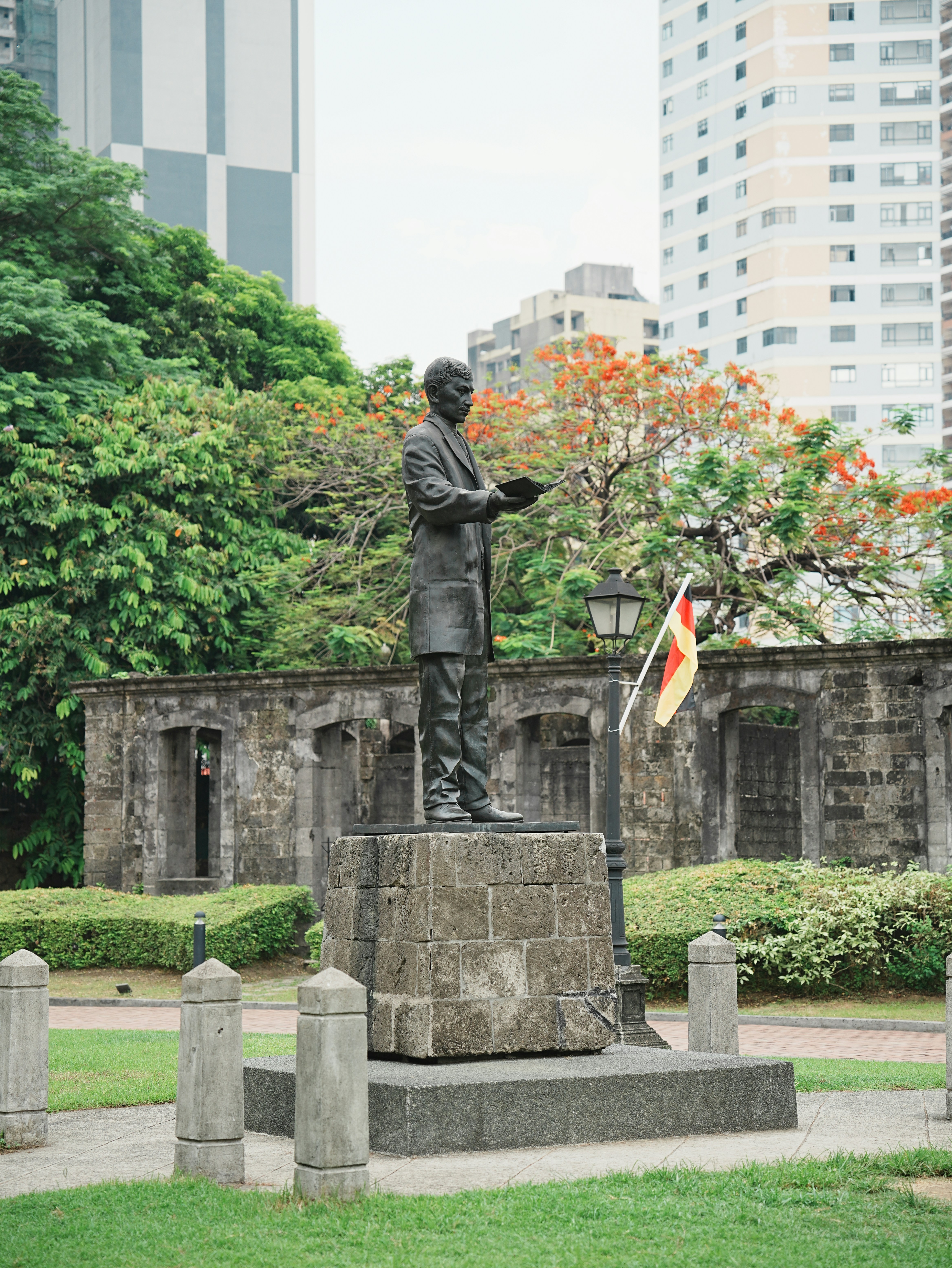 Statue of a Scholar in Urban Park Framed by Modern Towers