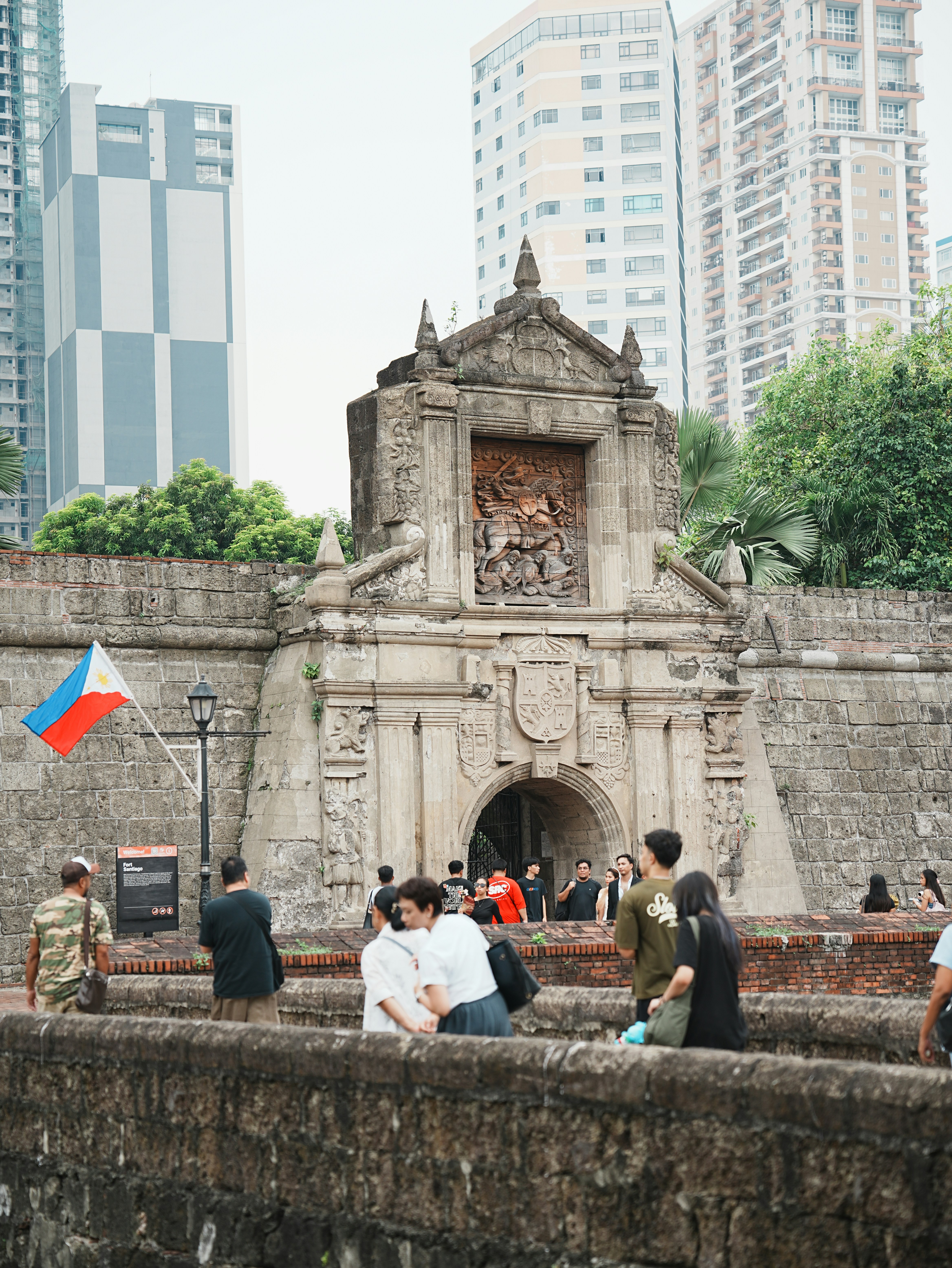 Stone Gatehouse Amid Skyline: Visitors at a Colonial Fort Entrance