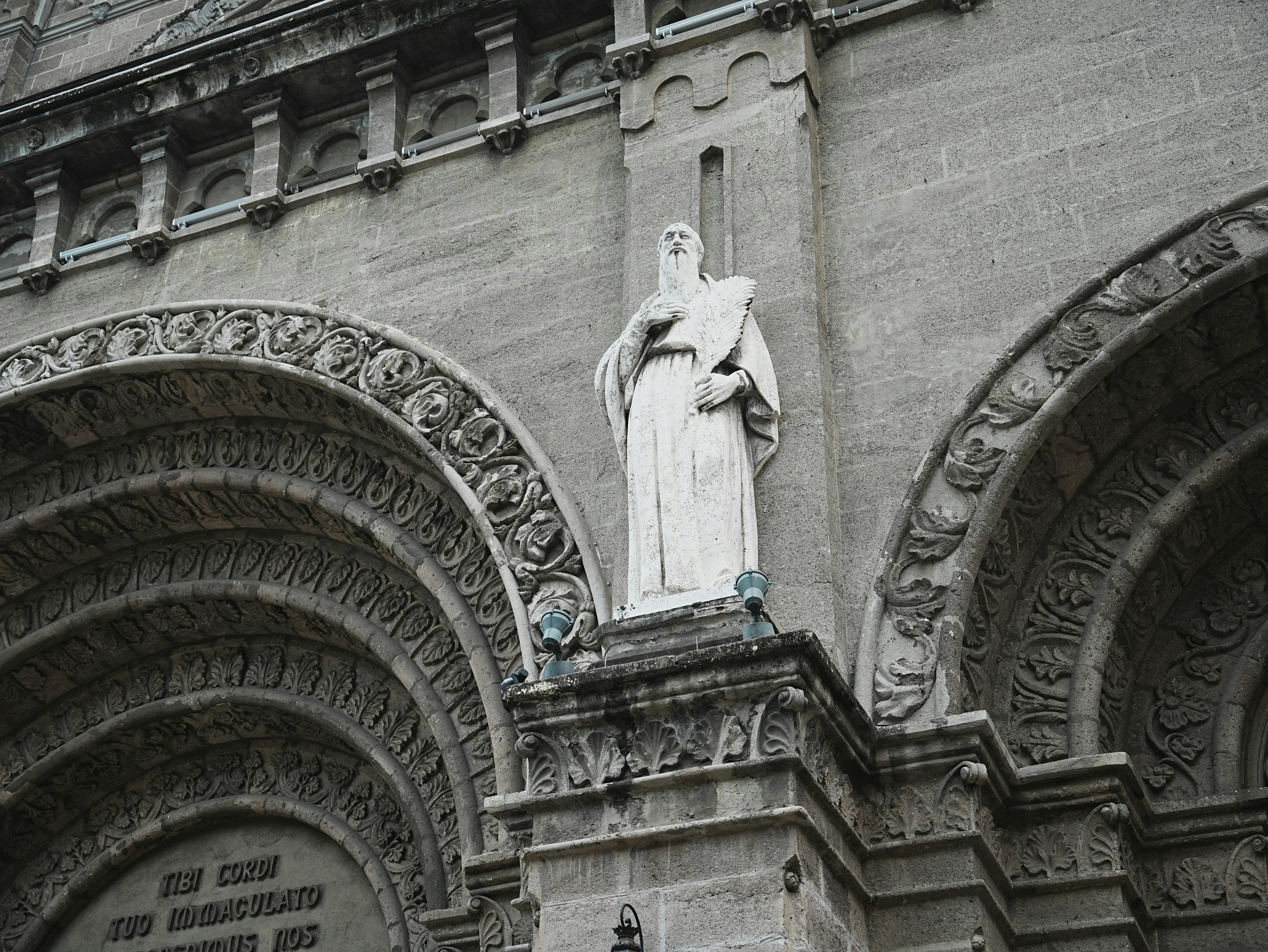 Stone Sentinel: A Gothic Proportioned Statuesque at the Church Facade