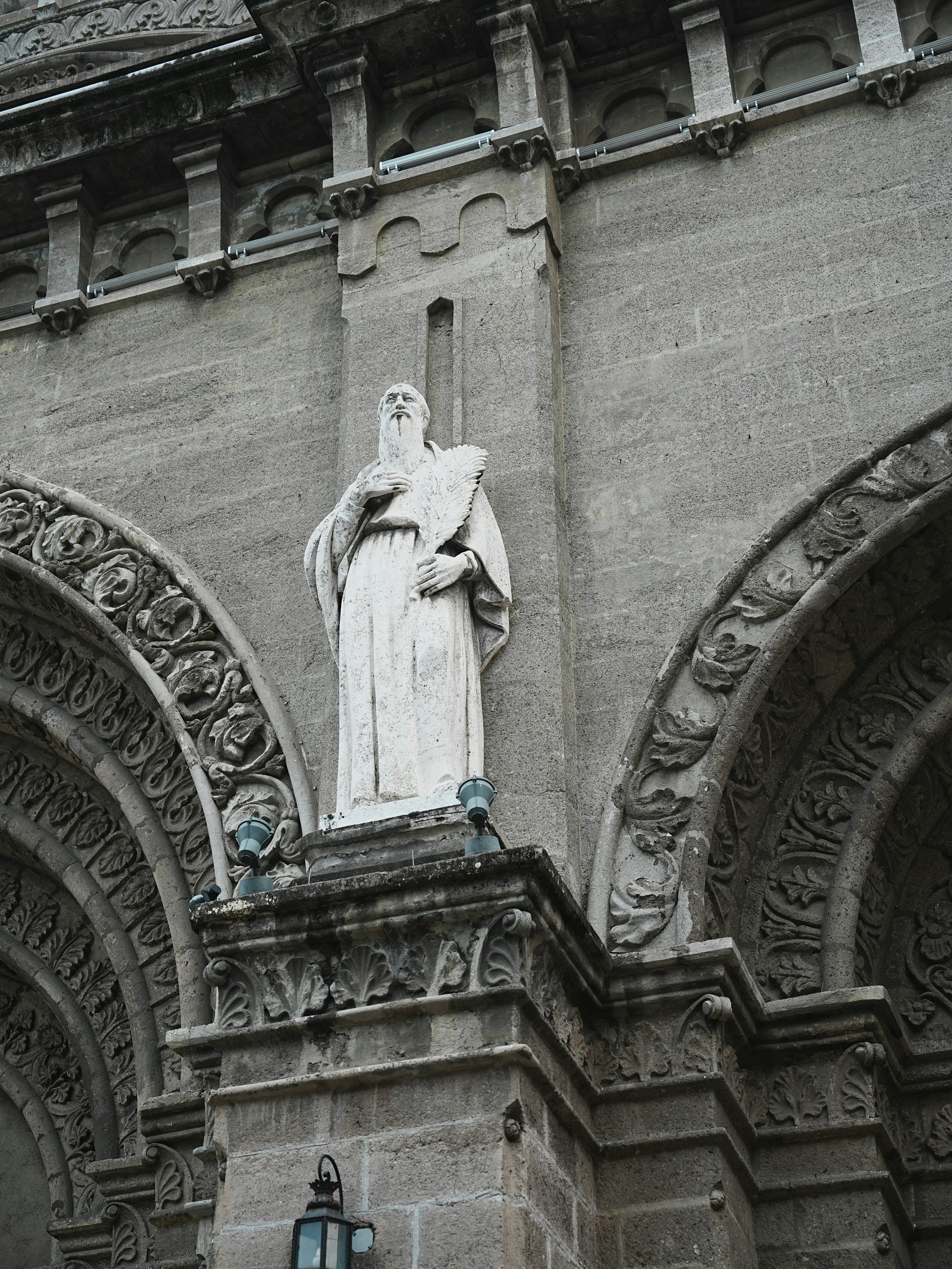 Stone Bishop: A Monumental Figure Under Carved Archways