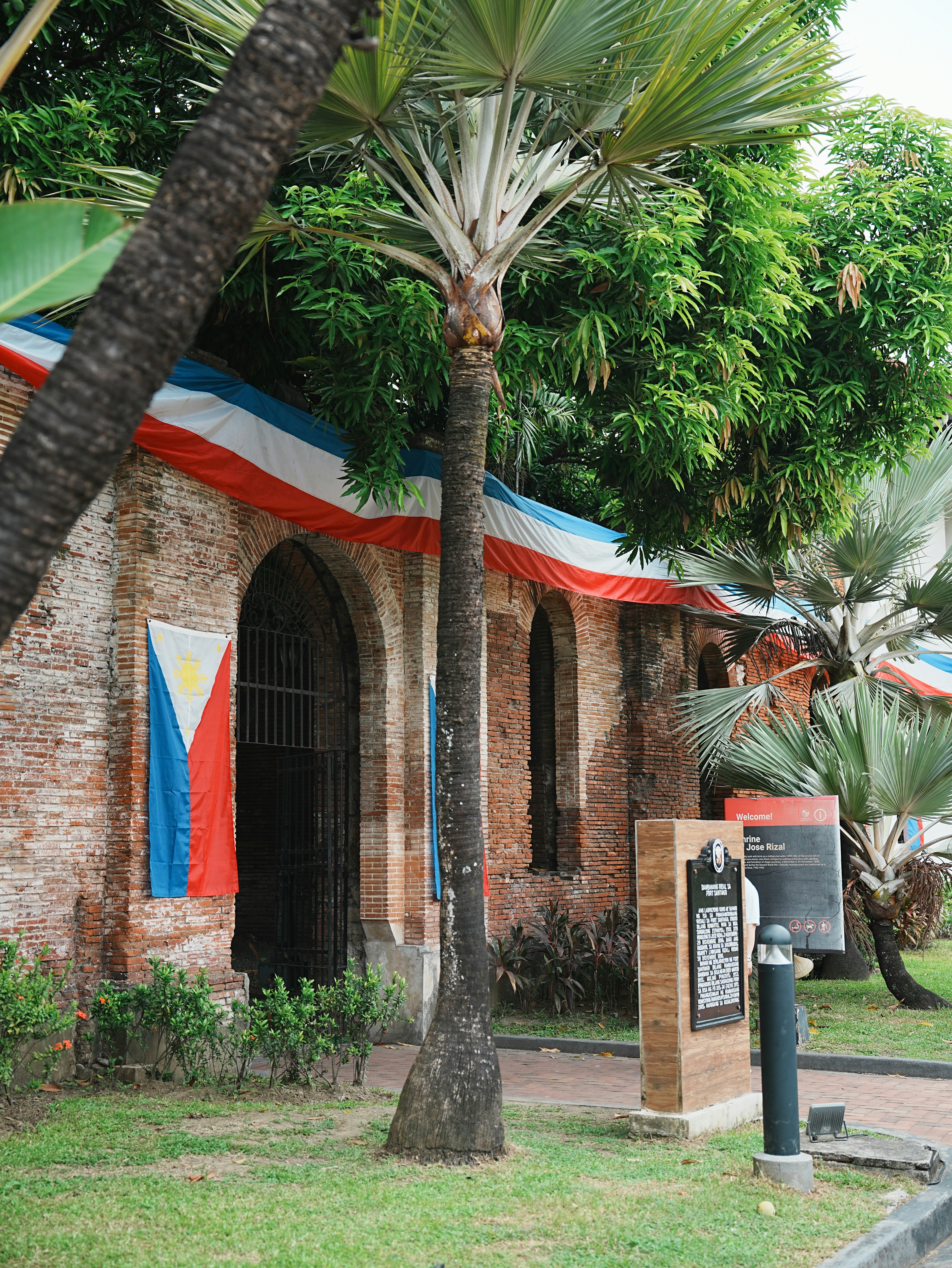 Arches of Brick and Banner: A Quiet Plaza Under Palm Fronds