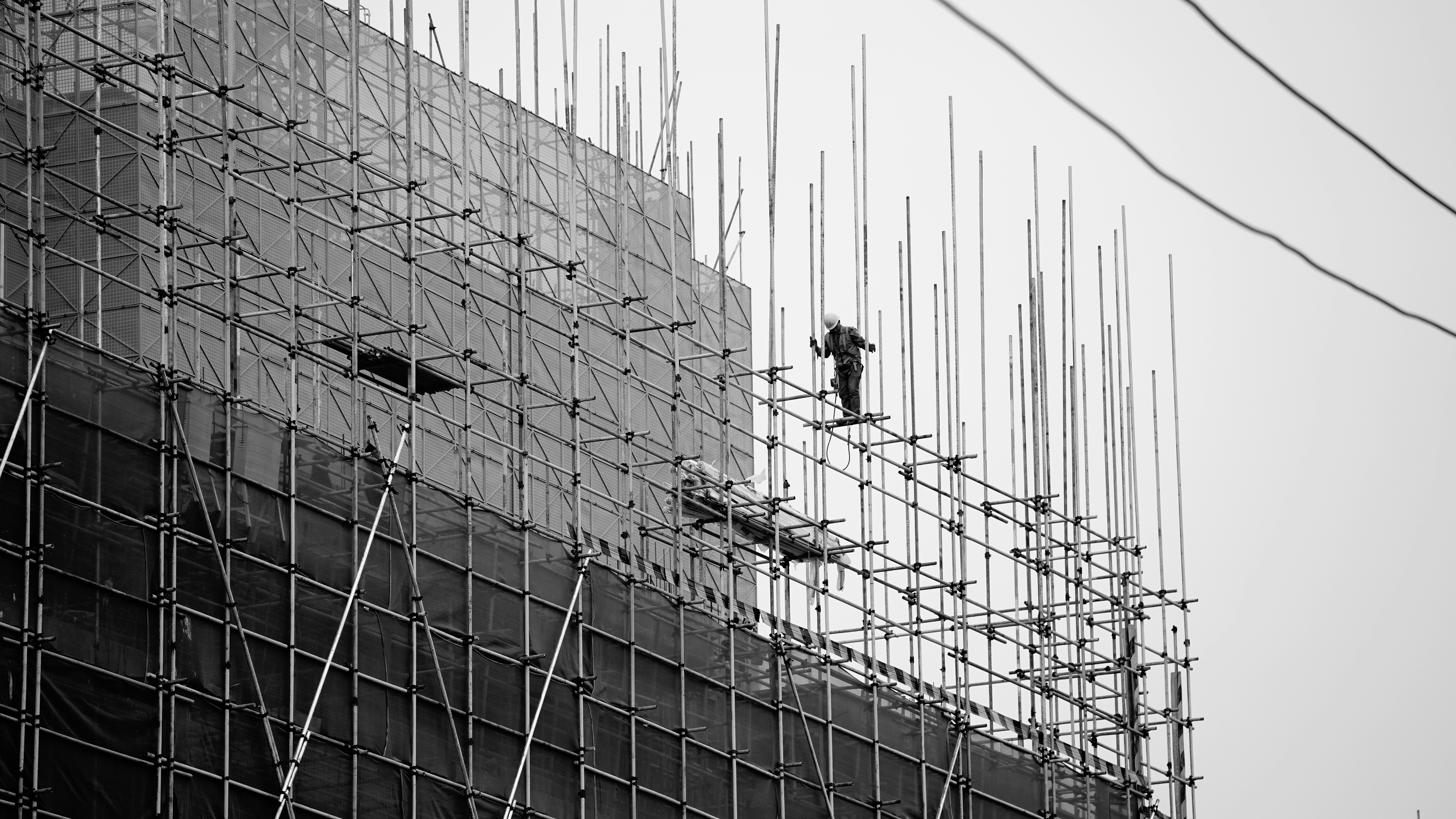 Worker Suspended in Concrete Framework Above a Grid of Steel Scaffolding