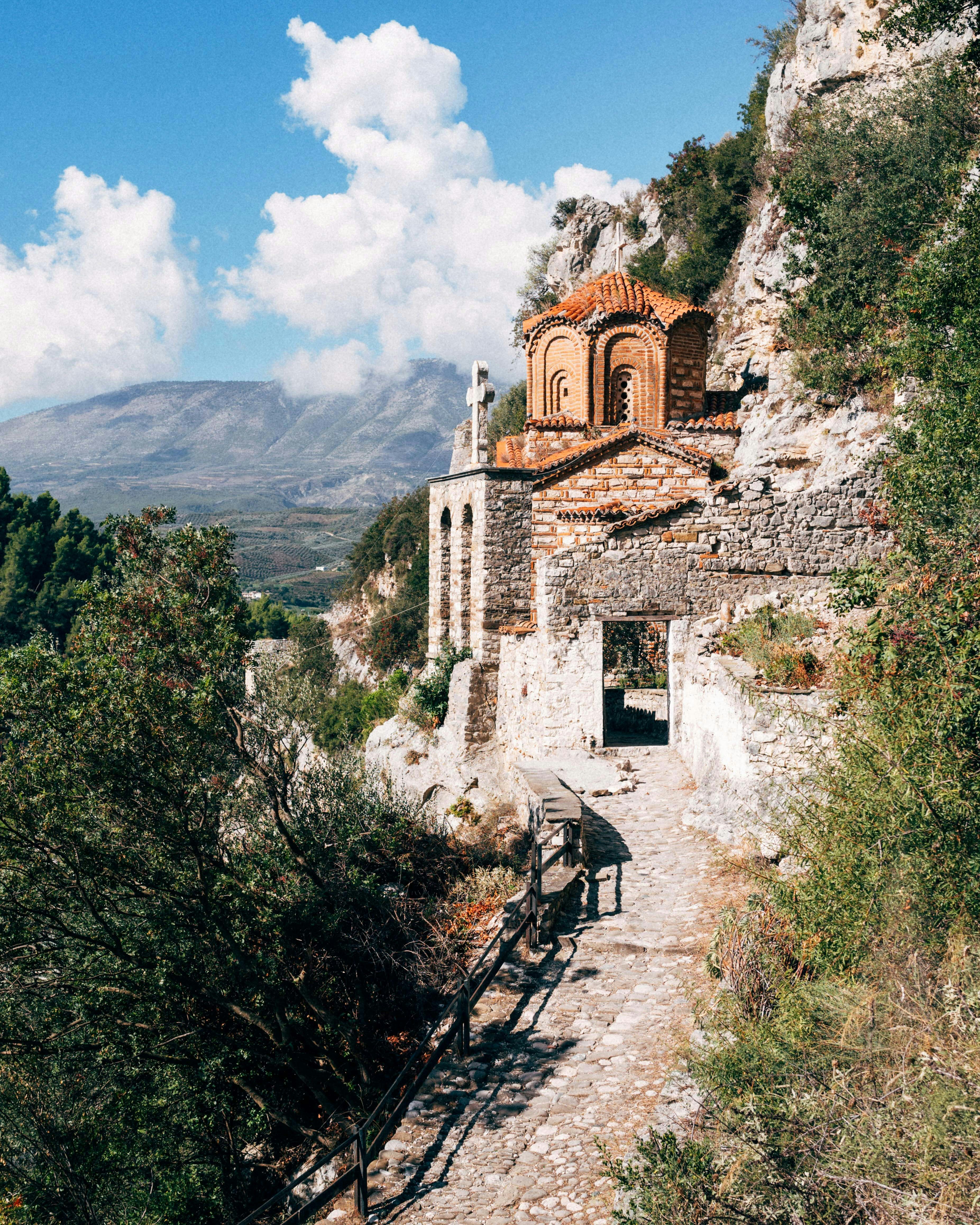 Ancient stone chapel tucked along a sunlit cliff path