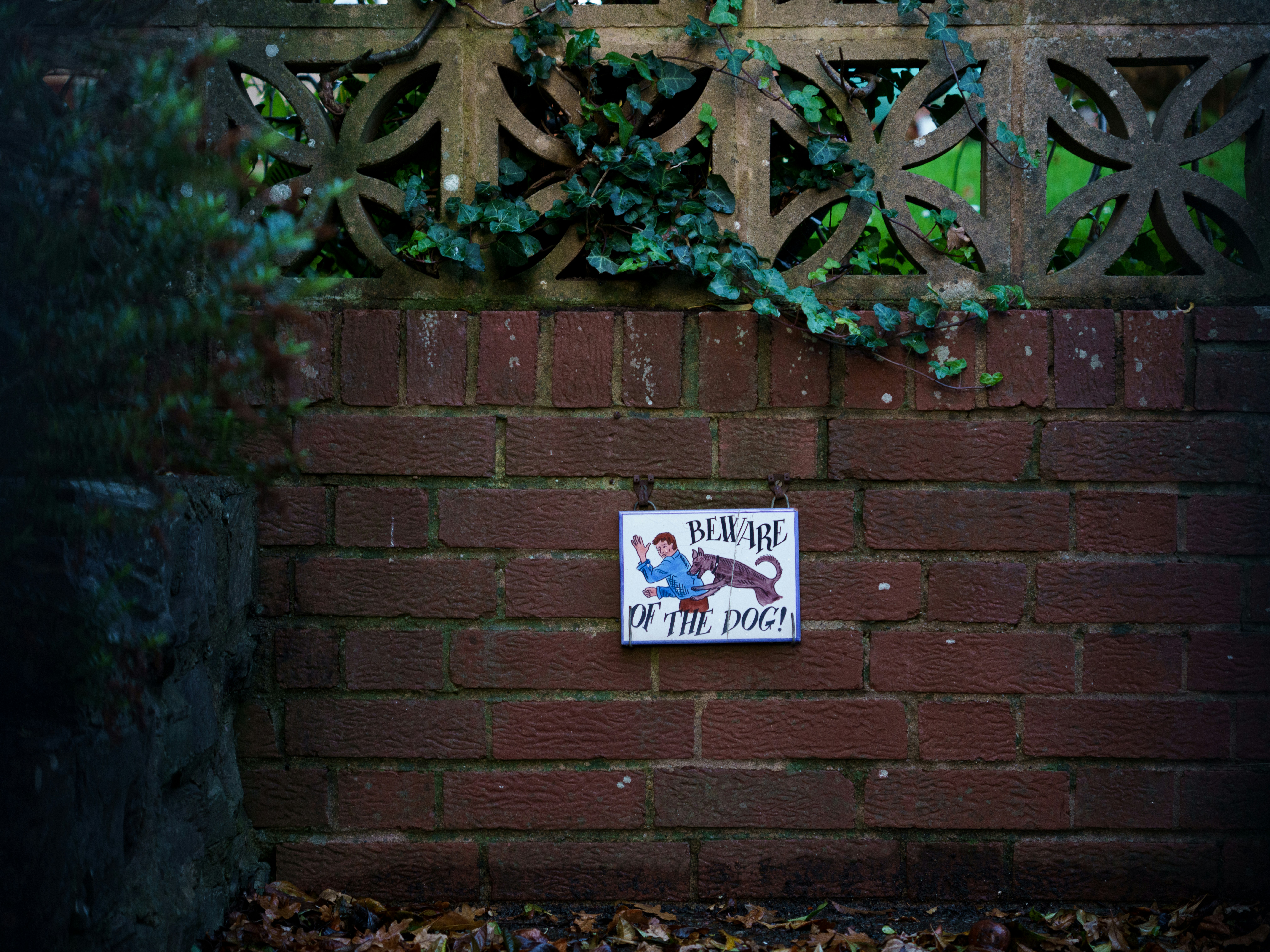 Beware of the Prowling Dog Sign on the Brick Wall