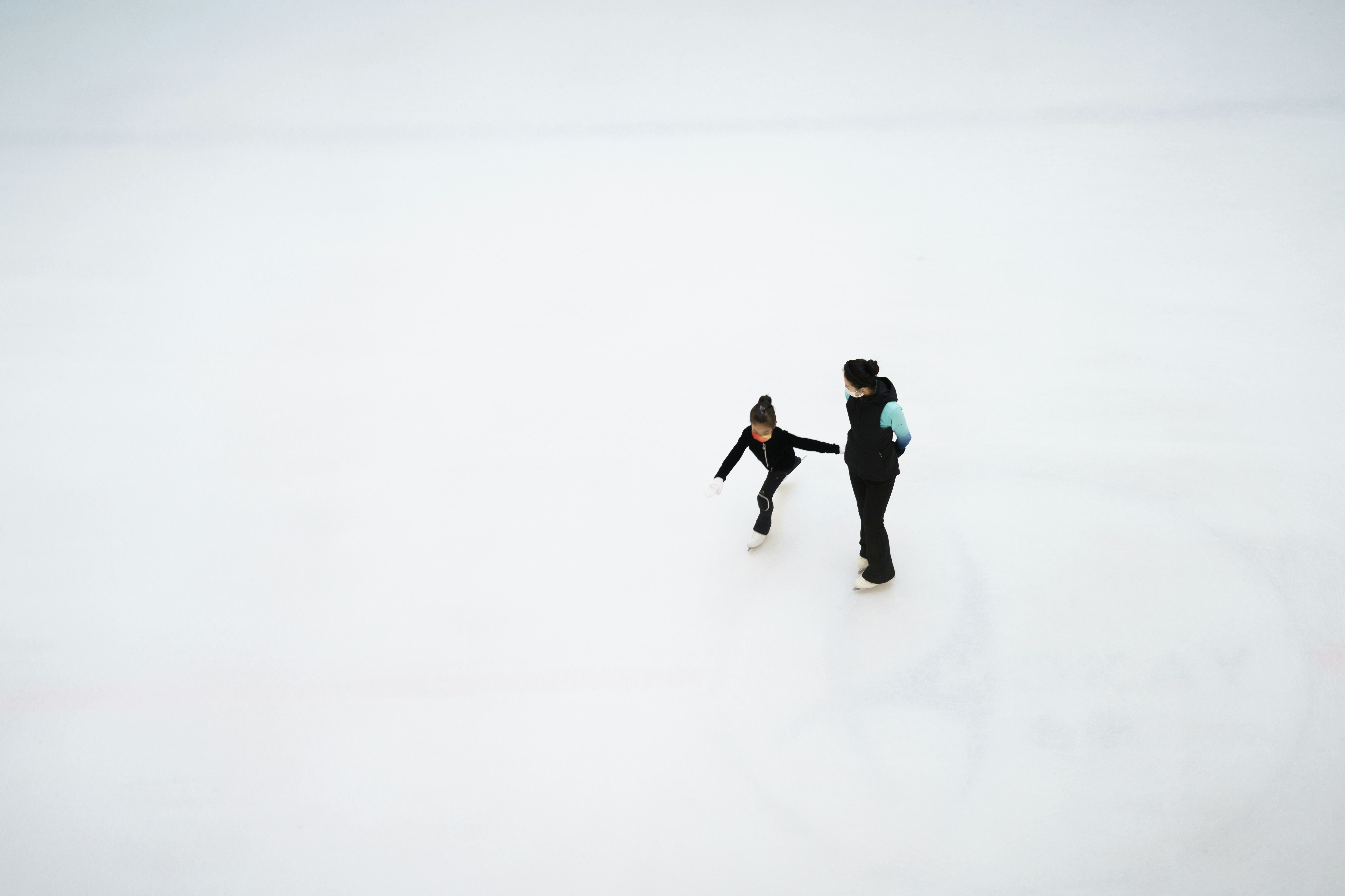 Duo in a pale winter canvas: a distant, intimate moment on ice
