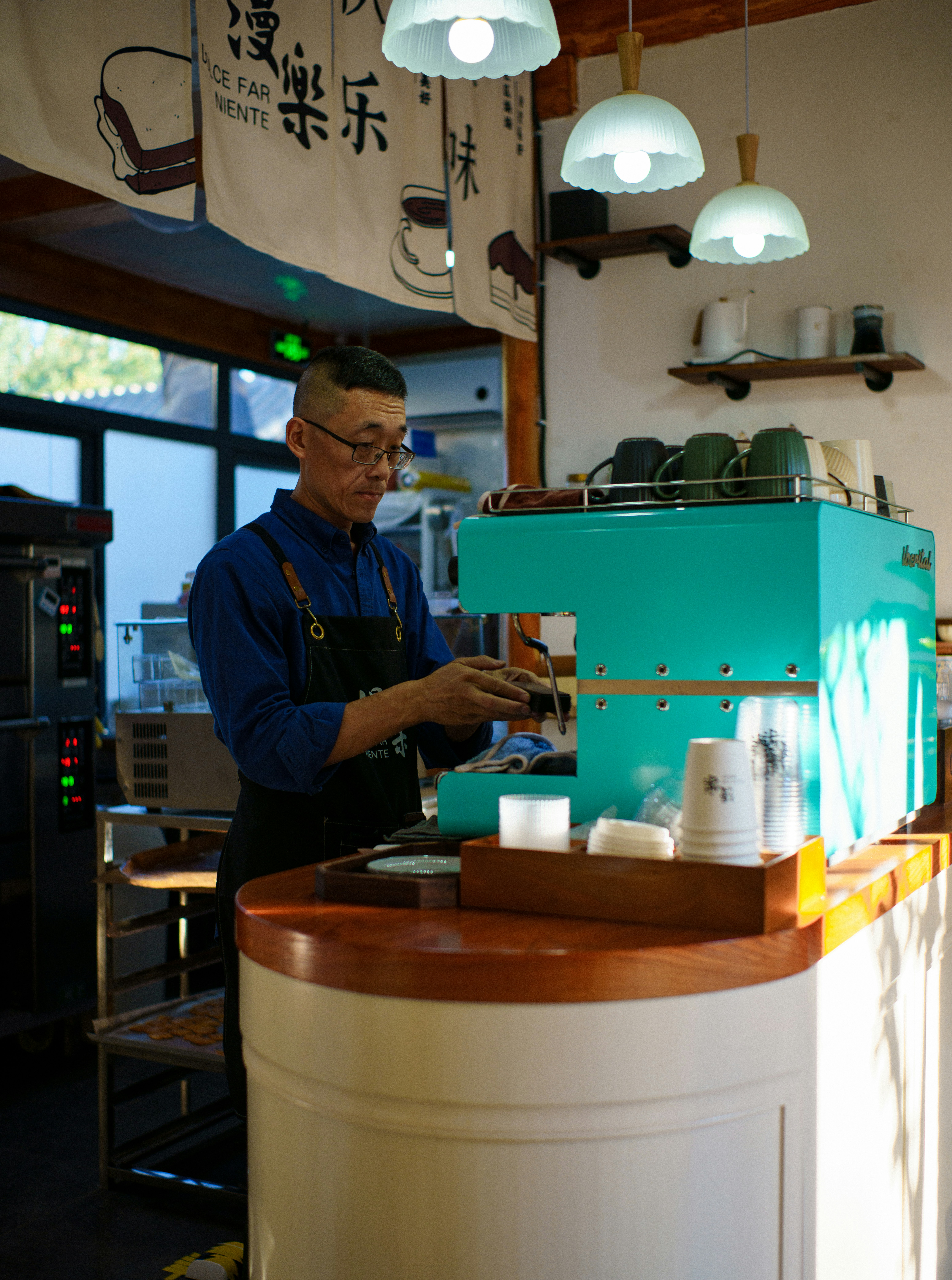 Barista at teal espresso machine: craft and calm in a sunlit cafe
