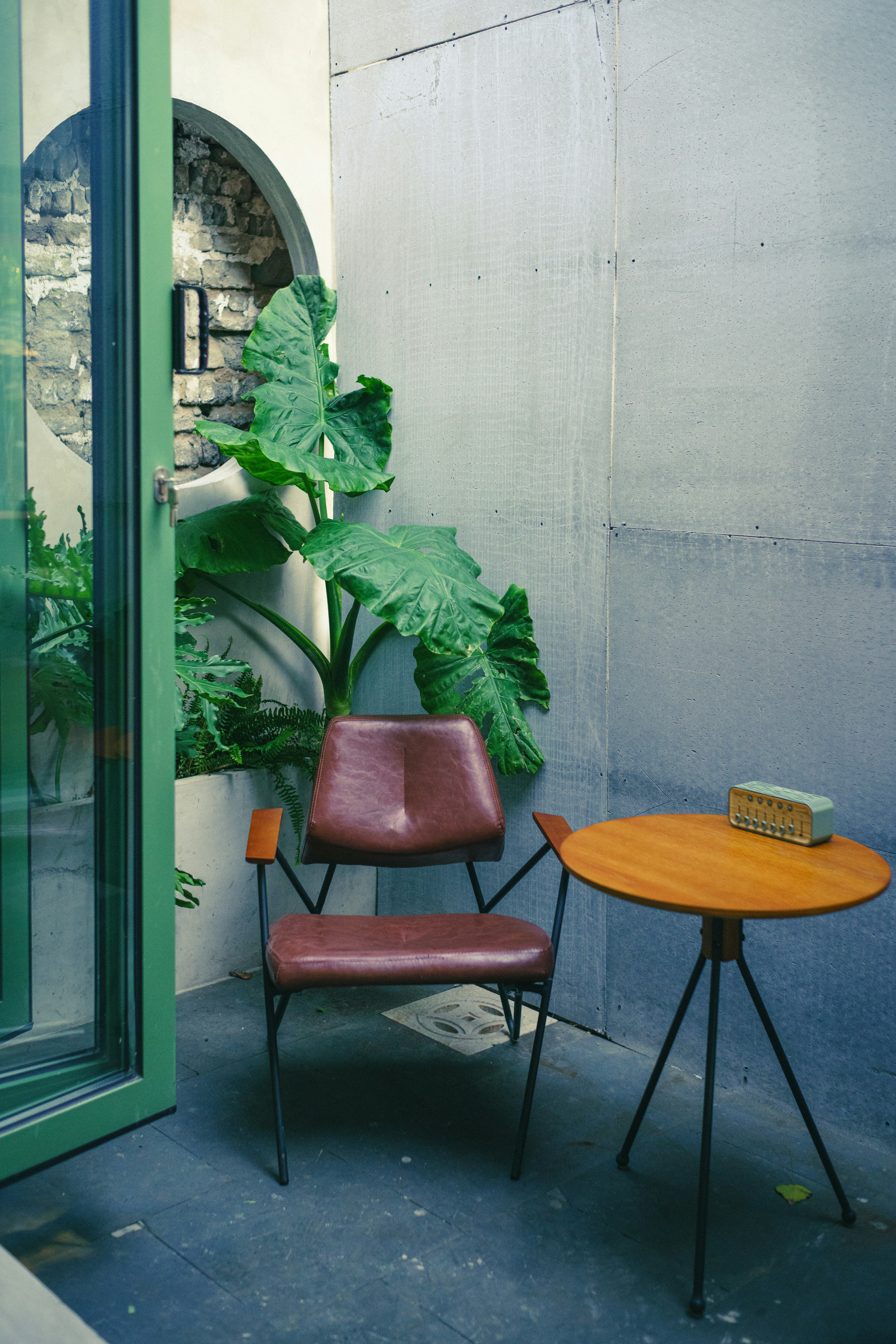Green Doorway Quiet: Vintage Chair and Round Table in a Concrete Balcony