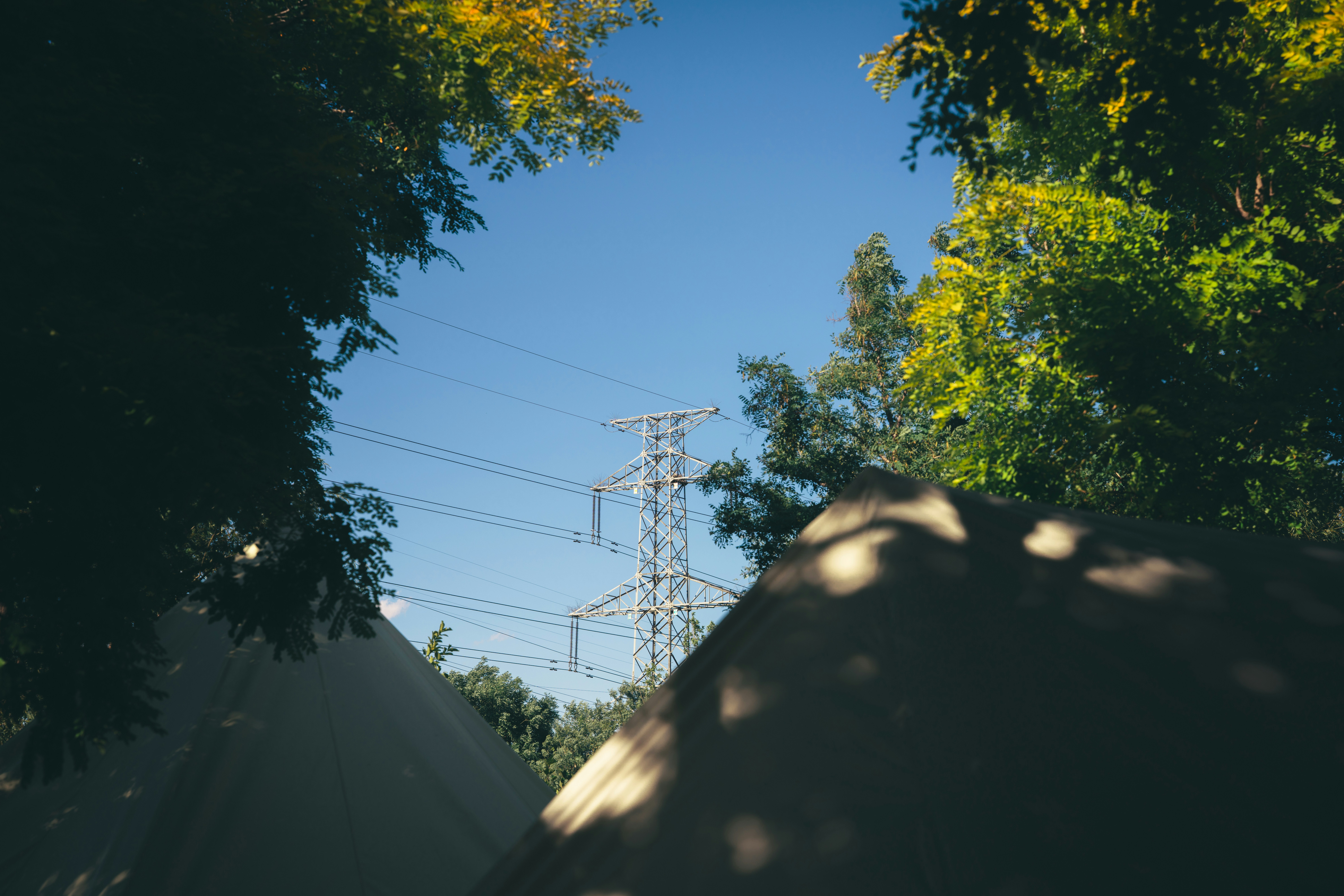 Power Lines Above the Campsite: Shadowed Tents under Sunlit Canopy