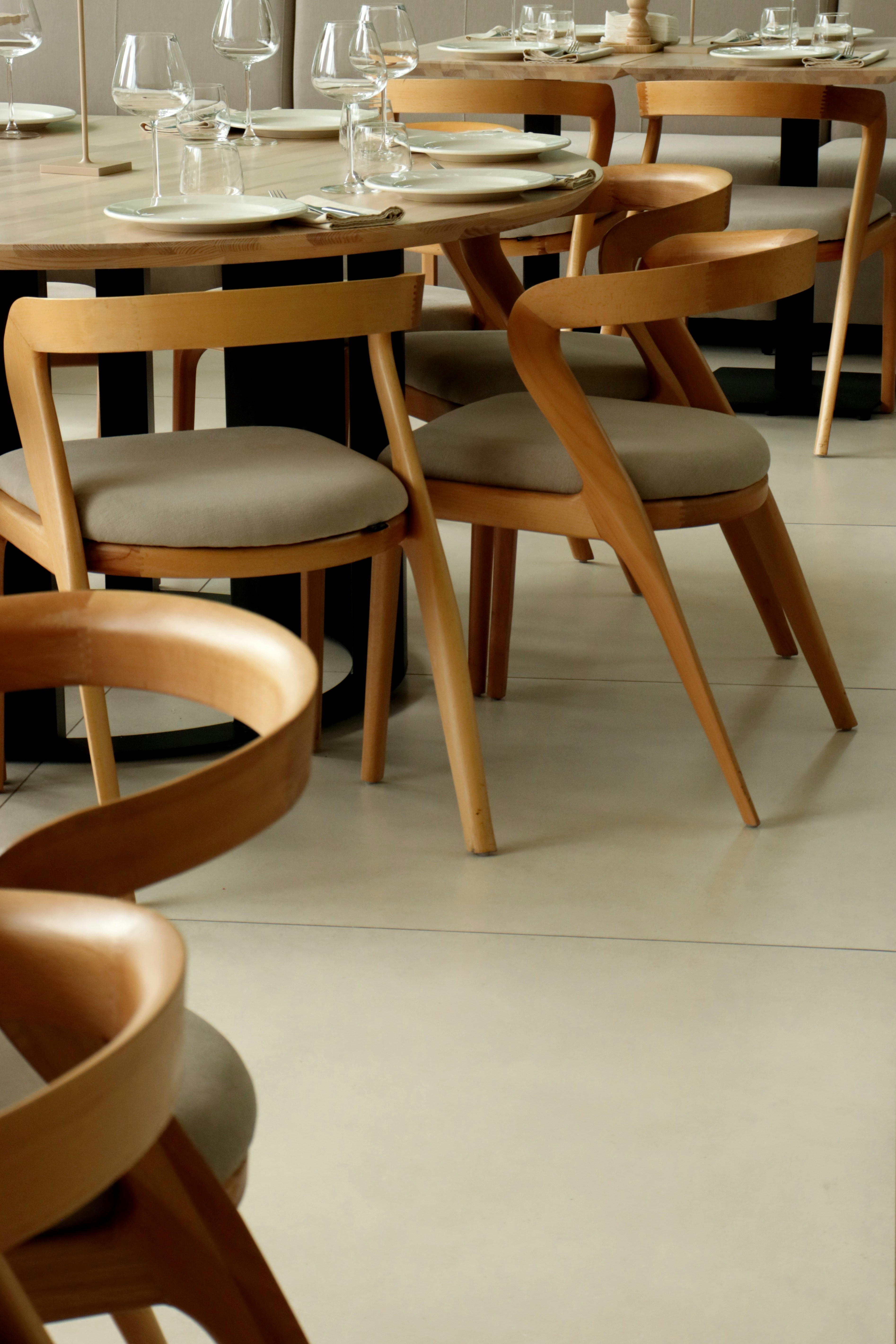 Curved wooden chairs encircle a sunlit dining table in a minimalist bistro