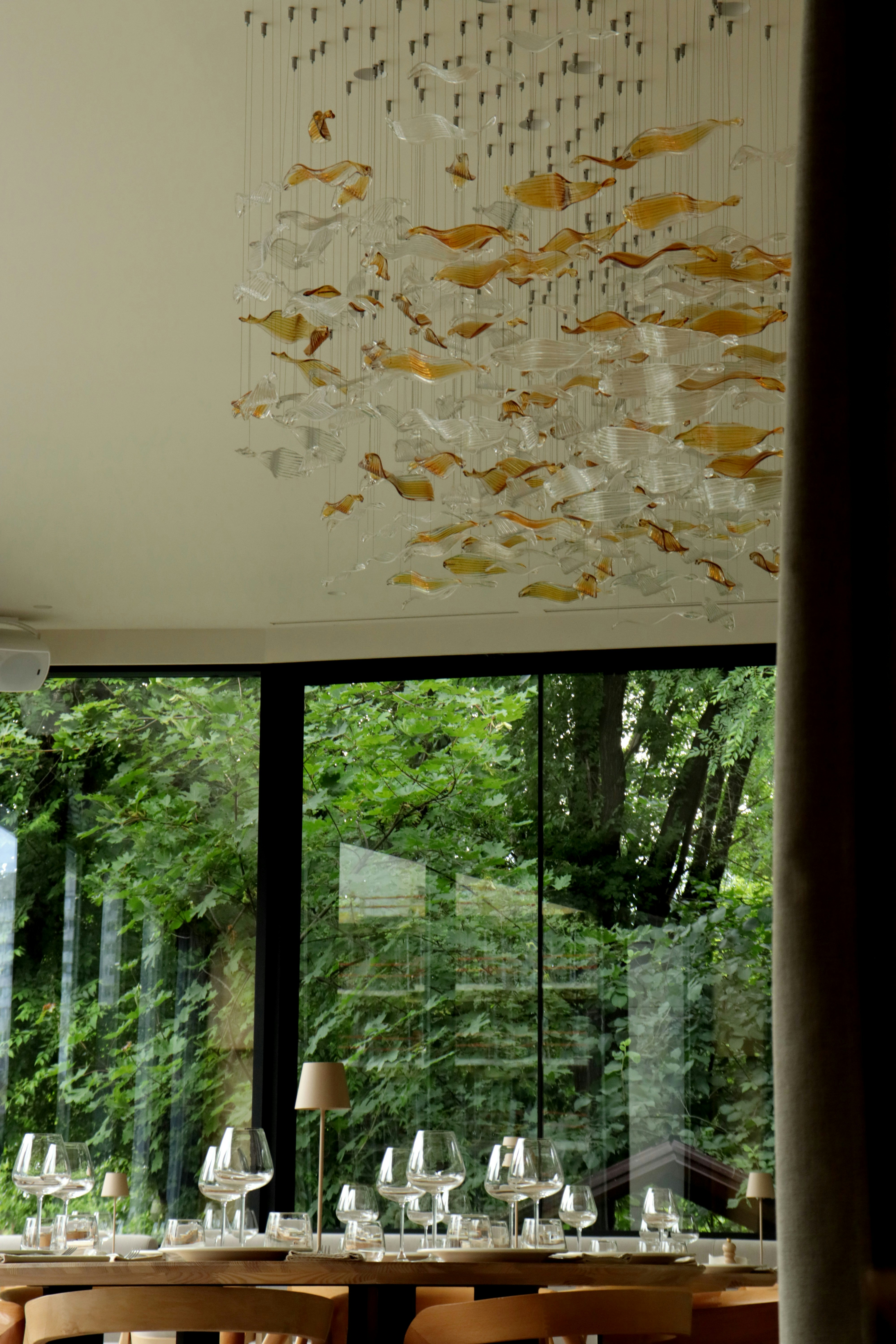Glass-ceiling chandelier over a sunlit restaurant